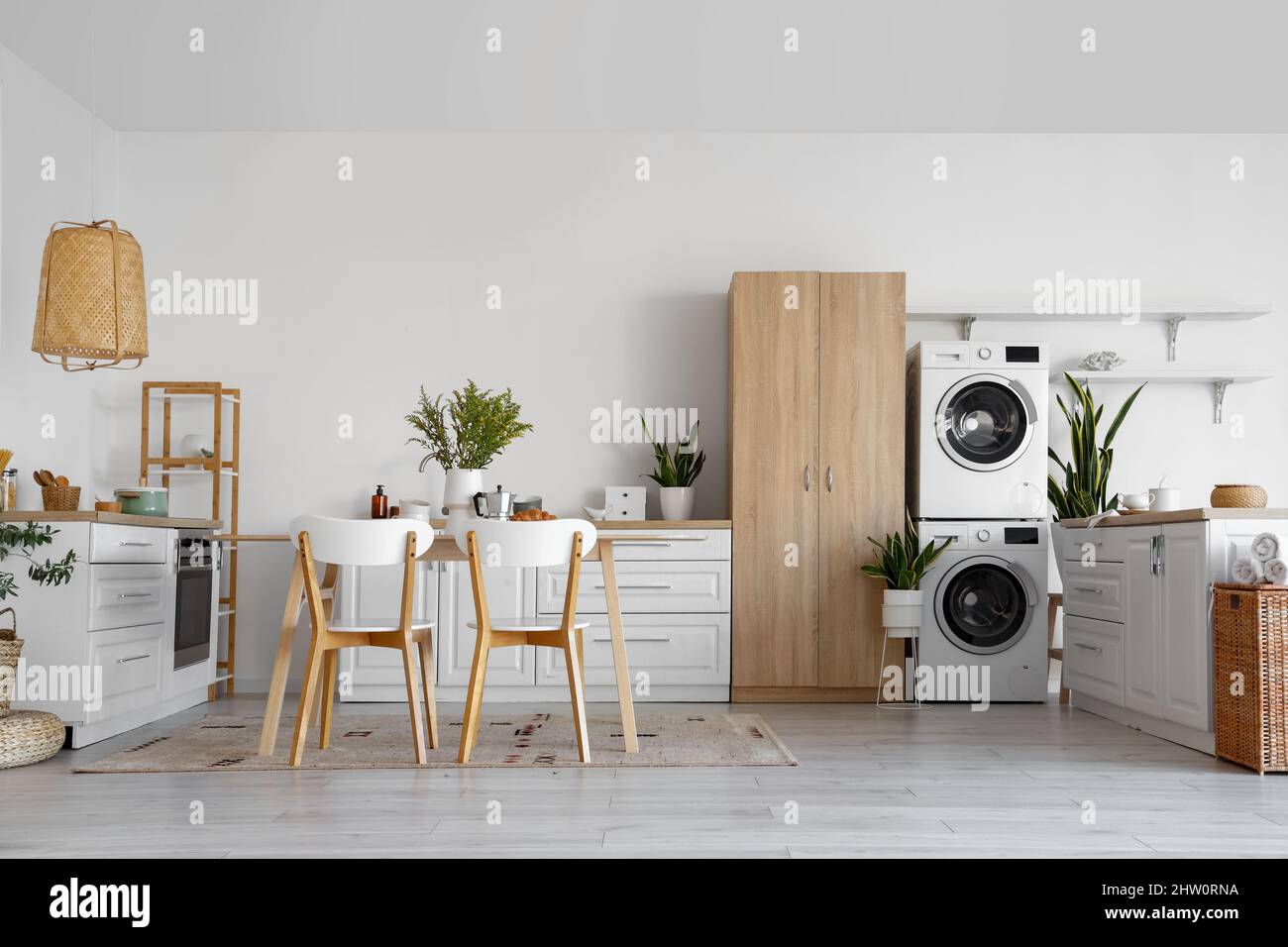 Interior of light kitchen with washing machines, dining table and ...