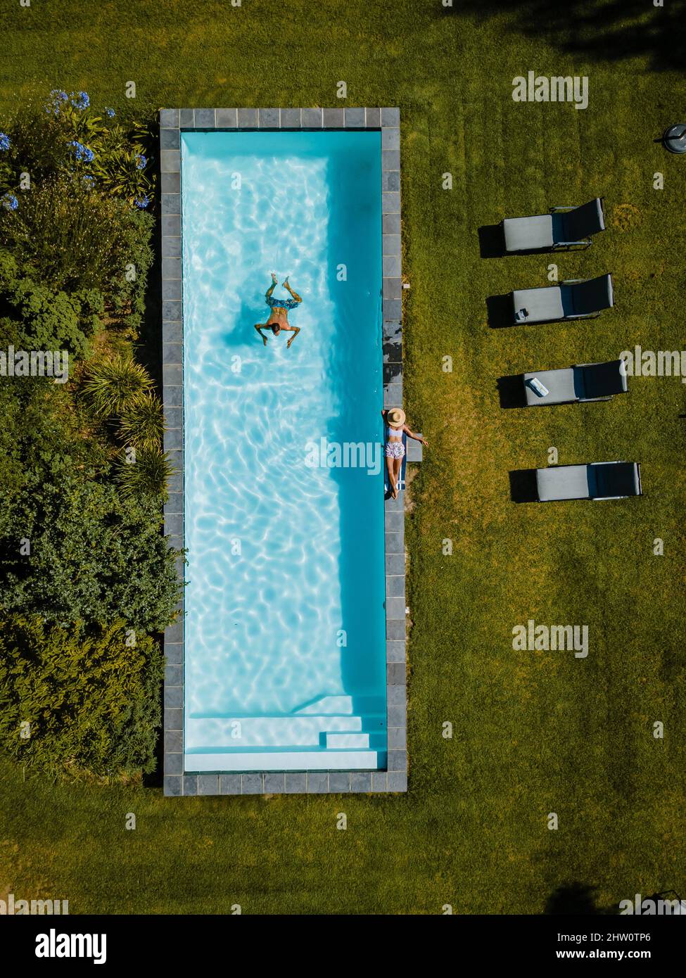 Drone view at swimming pool above with man and woman swimming ...