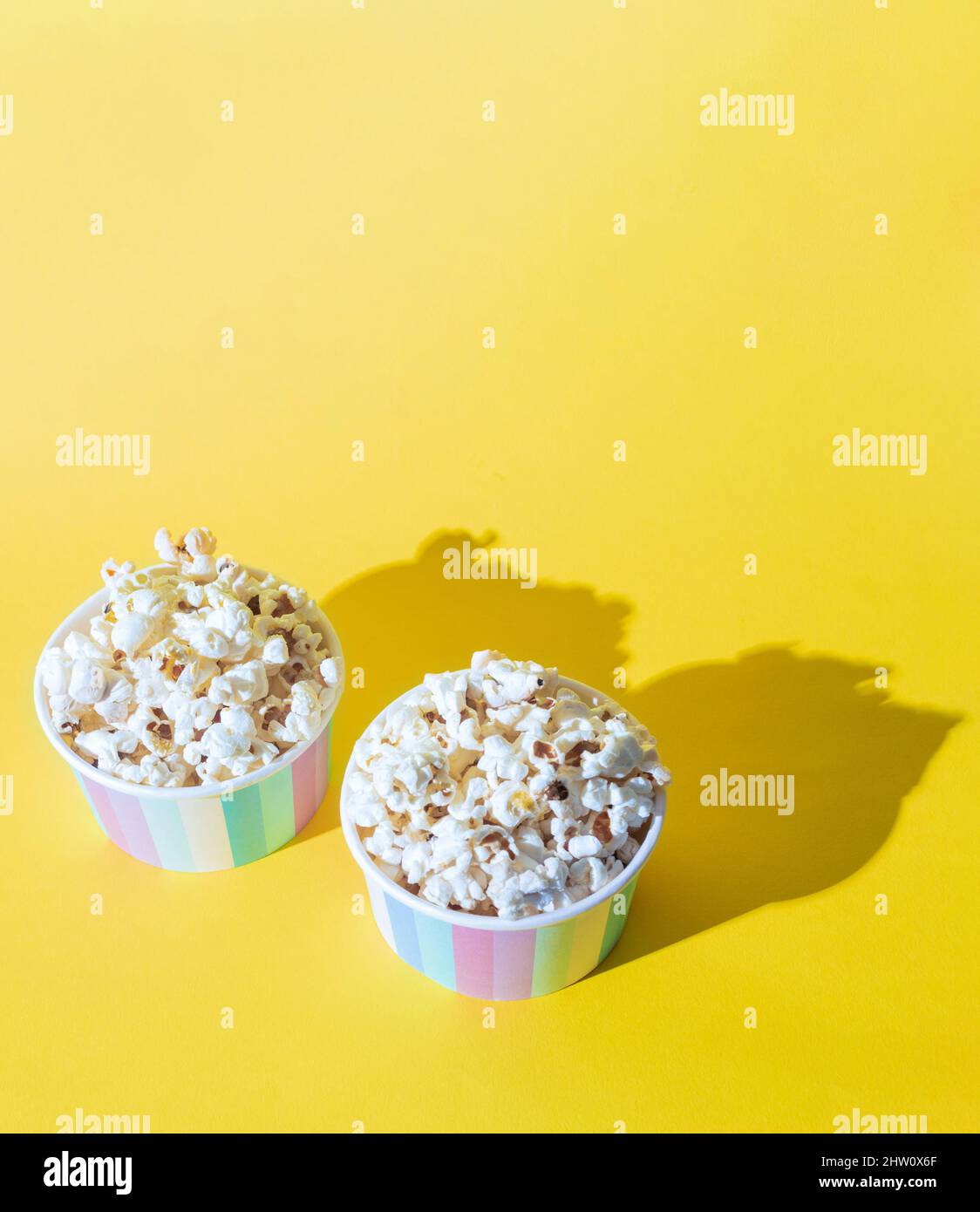Popcorn in a cardboard box on a yellow background. Popcorn on a yellow ...