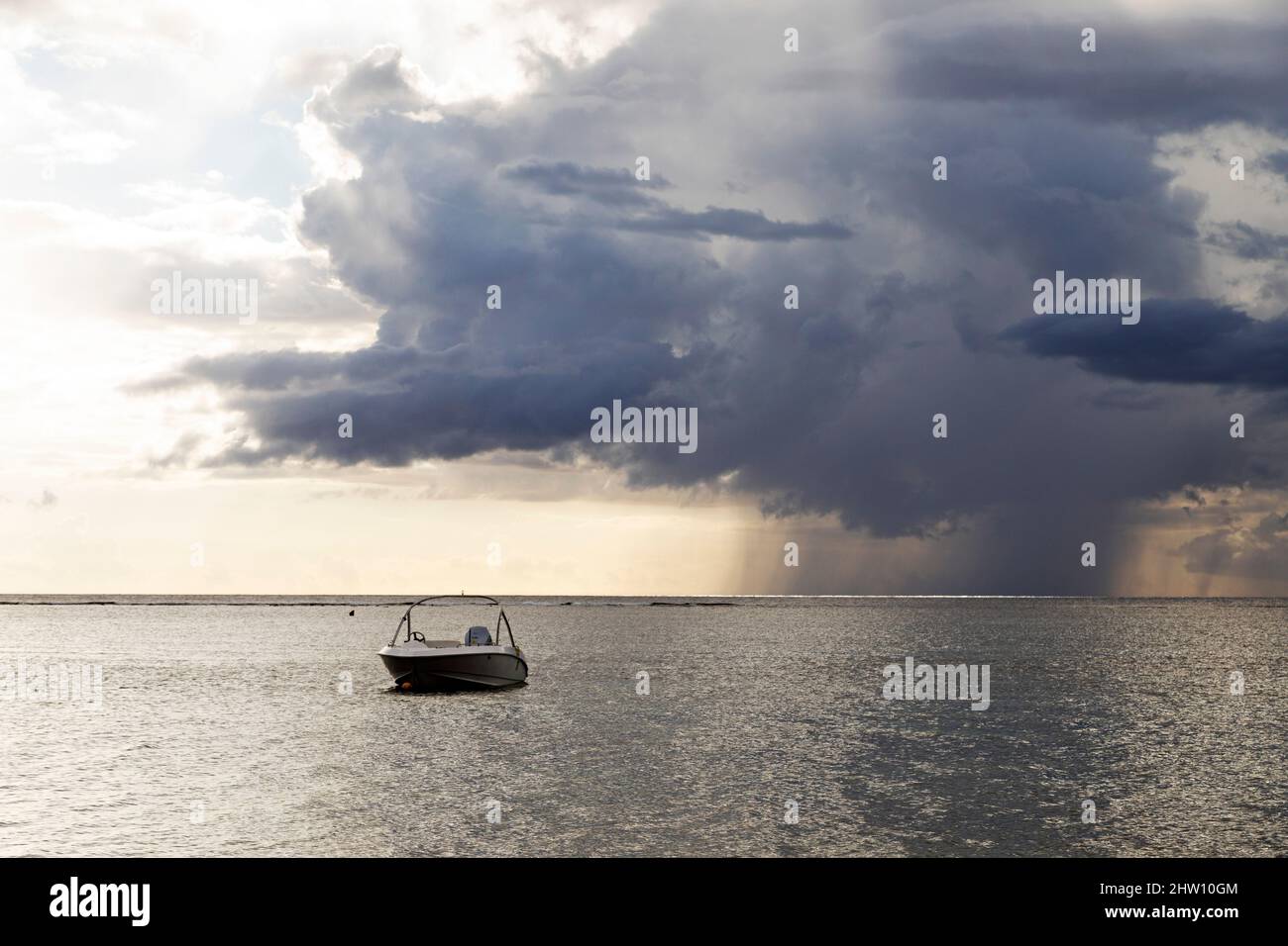 Rain clouds off the southwest coast of Mauritius. A boat floats in the ...