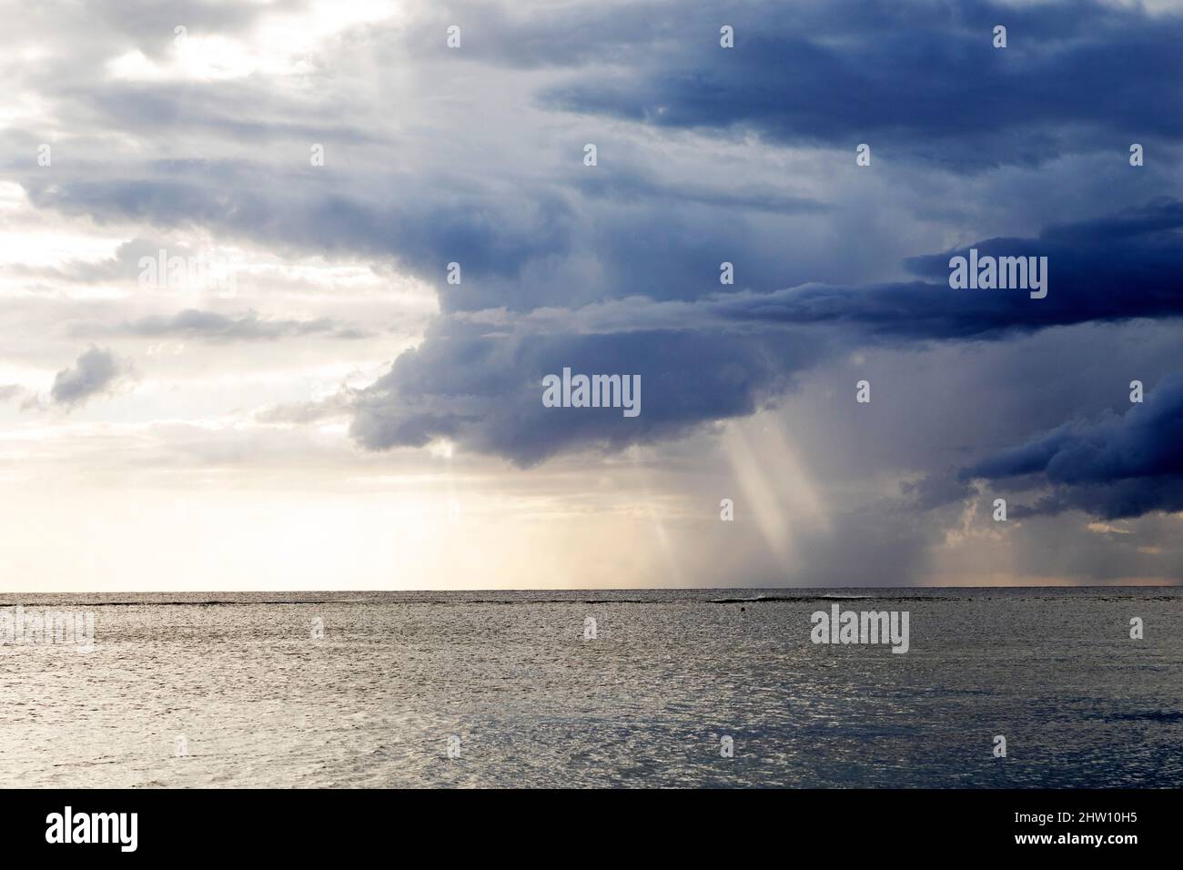 Sunlight bursts through rain clouds over the Indian Ocean off the south ...