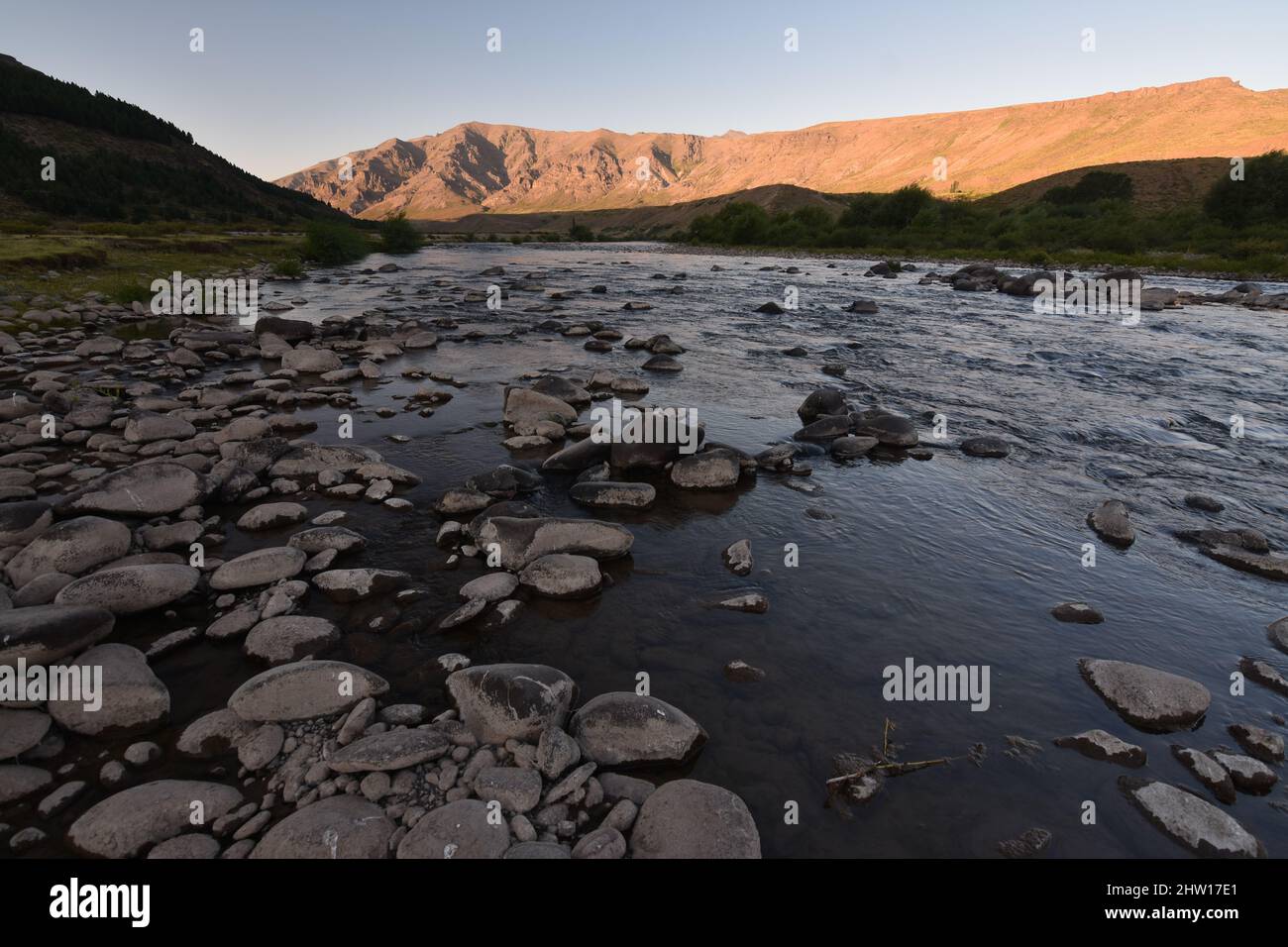 River during sunset with rocky mountains in the background Stock Photo ...