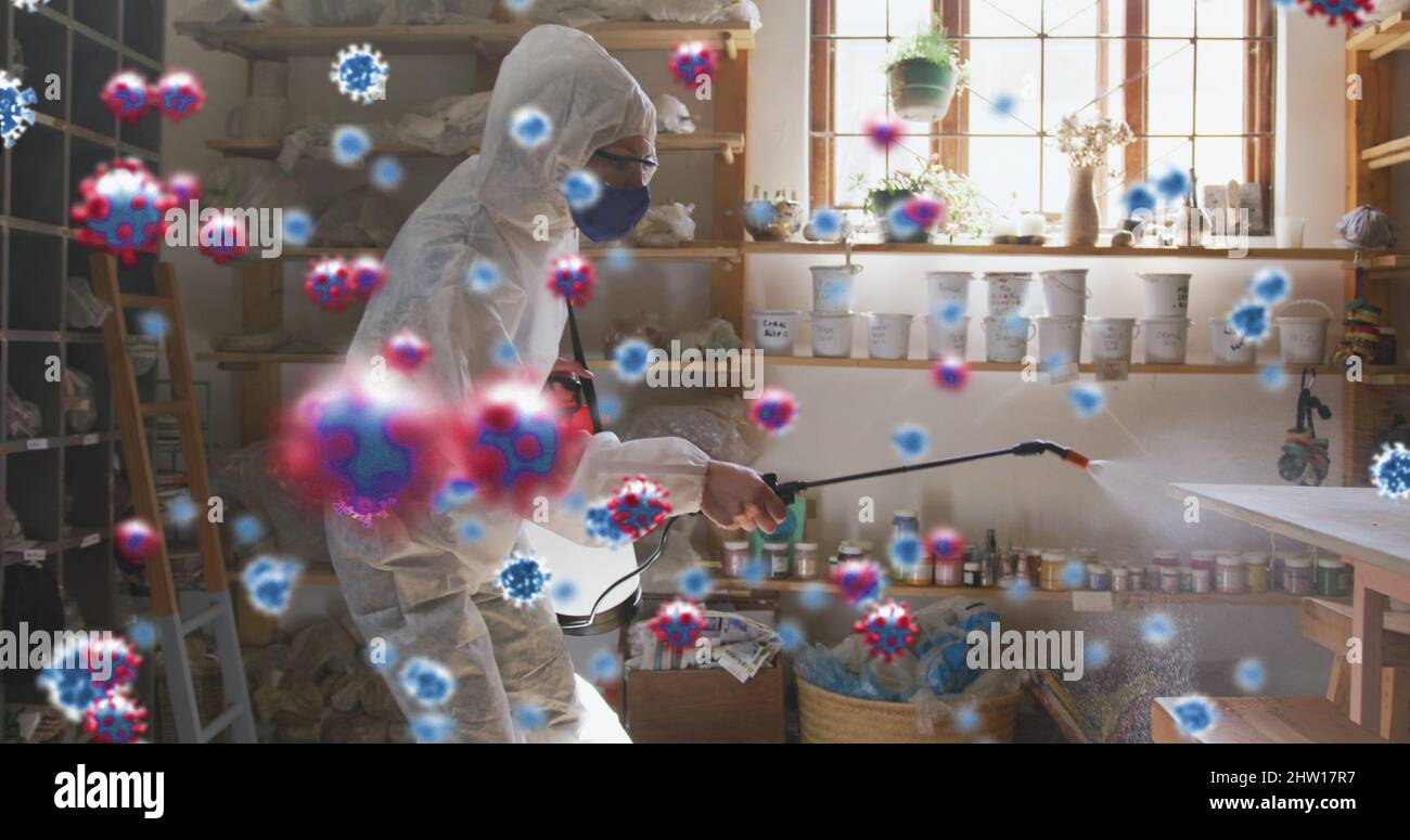 Image of covid 19 cells over person wearing ppe suit and face mask ...