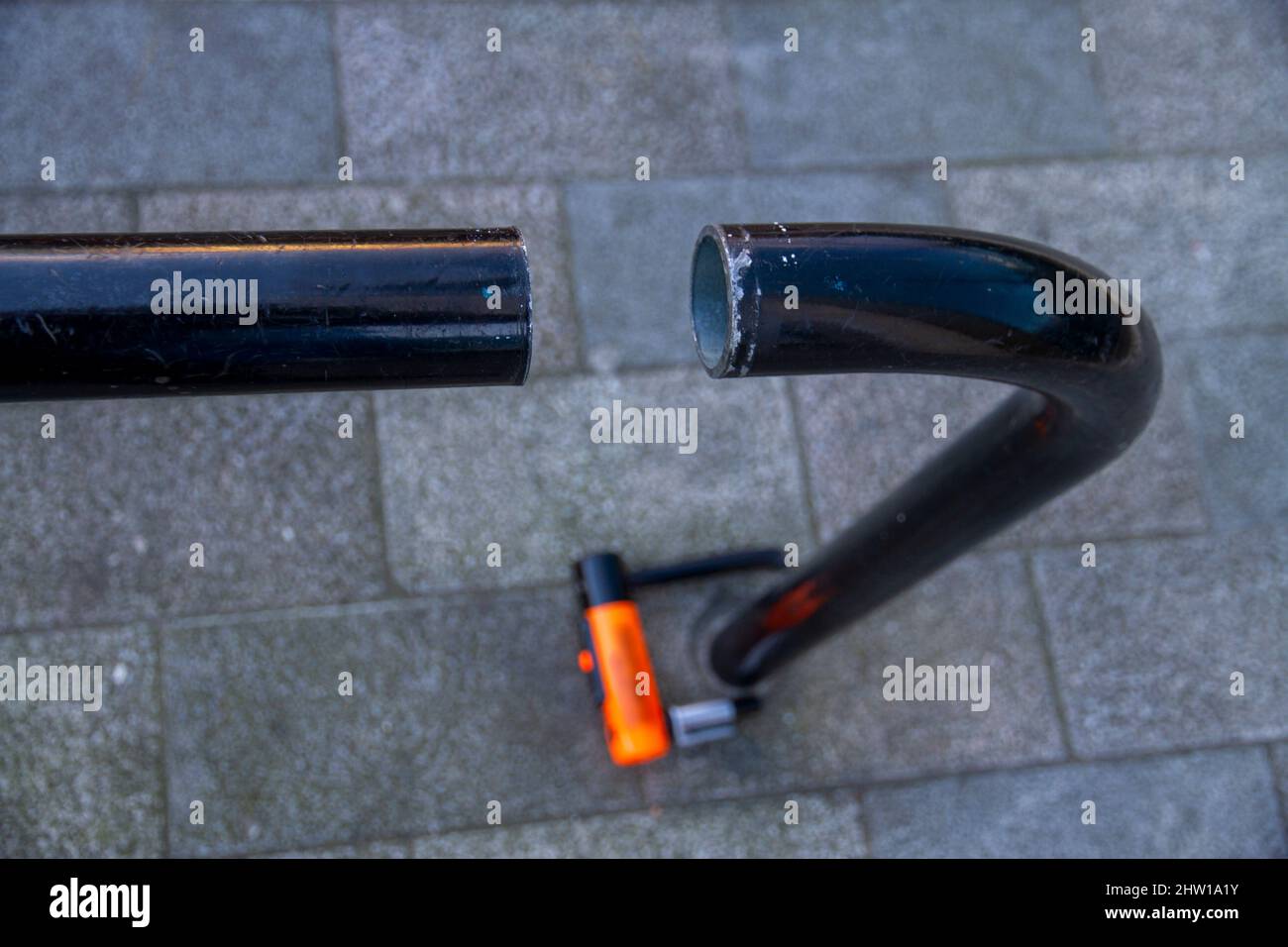 View of a broken bike stand with a broken D-lock on the ground below ...