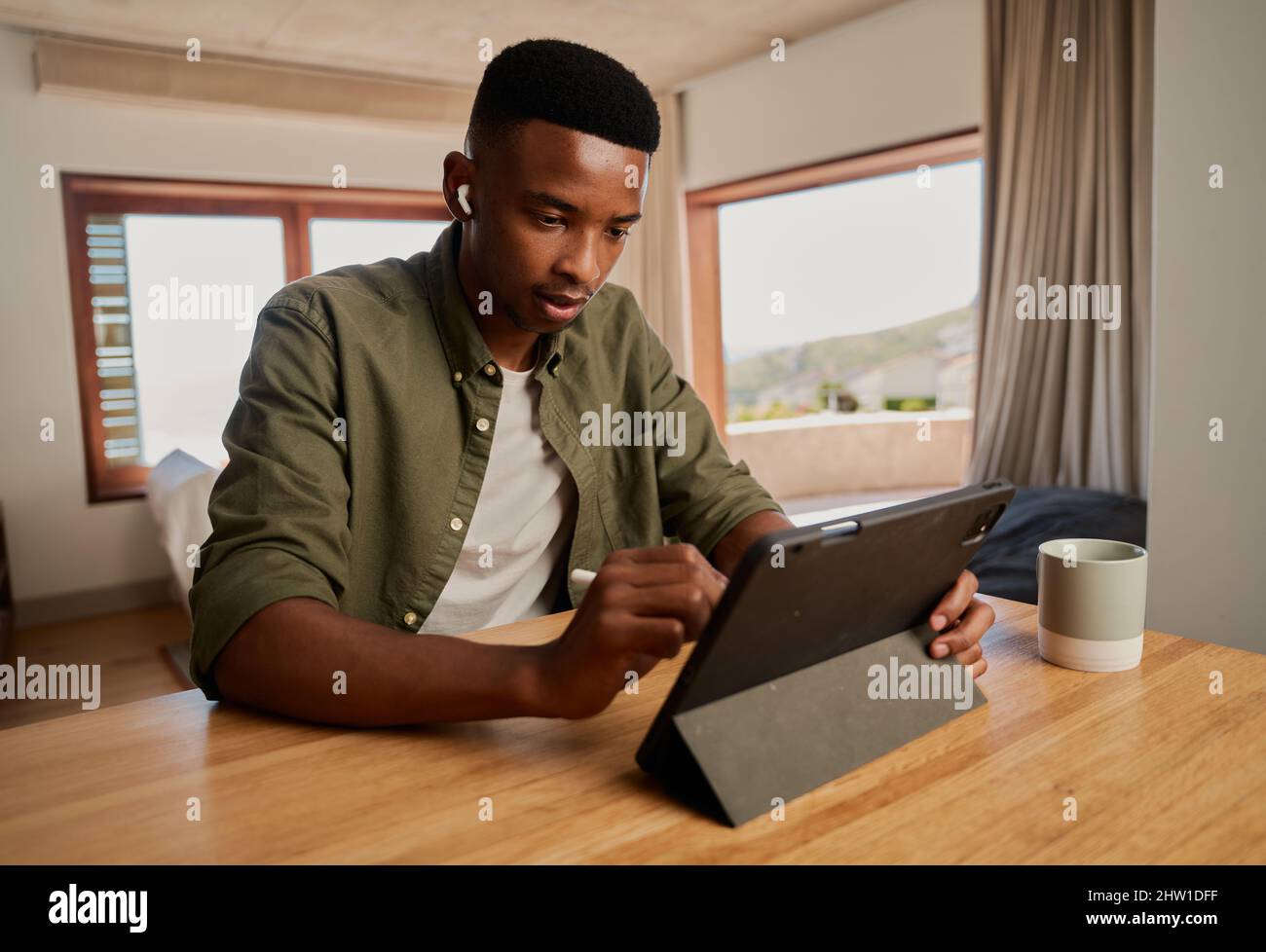 Young adult black male using pen to write on electronic tablet ...