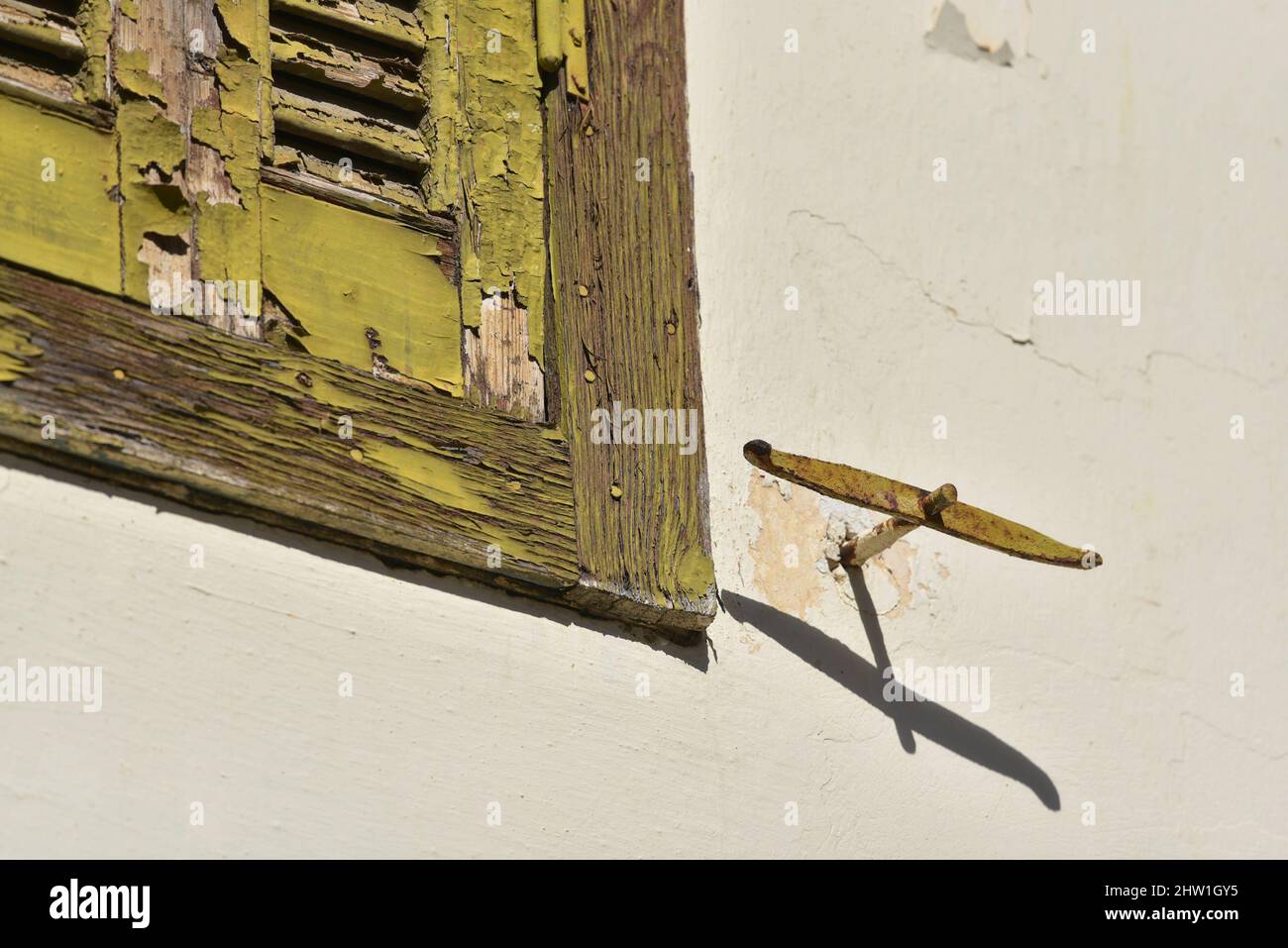 Old rural house weathered wooden window shutter with chipped chartreuse ...