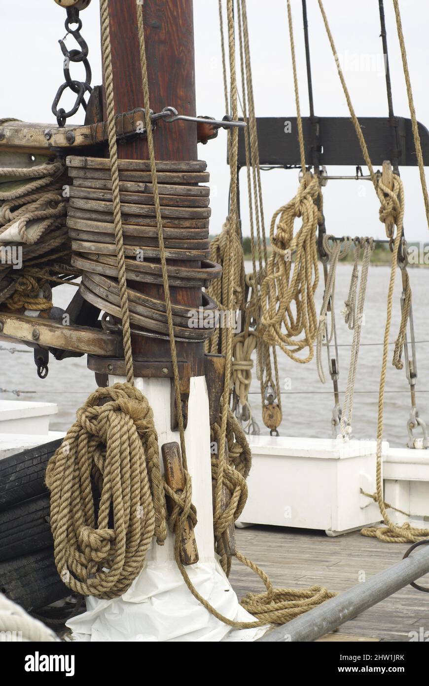 Vertical shot of ship mast with chain links and ropes with gray sea on ...