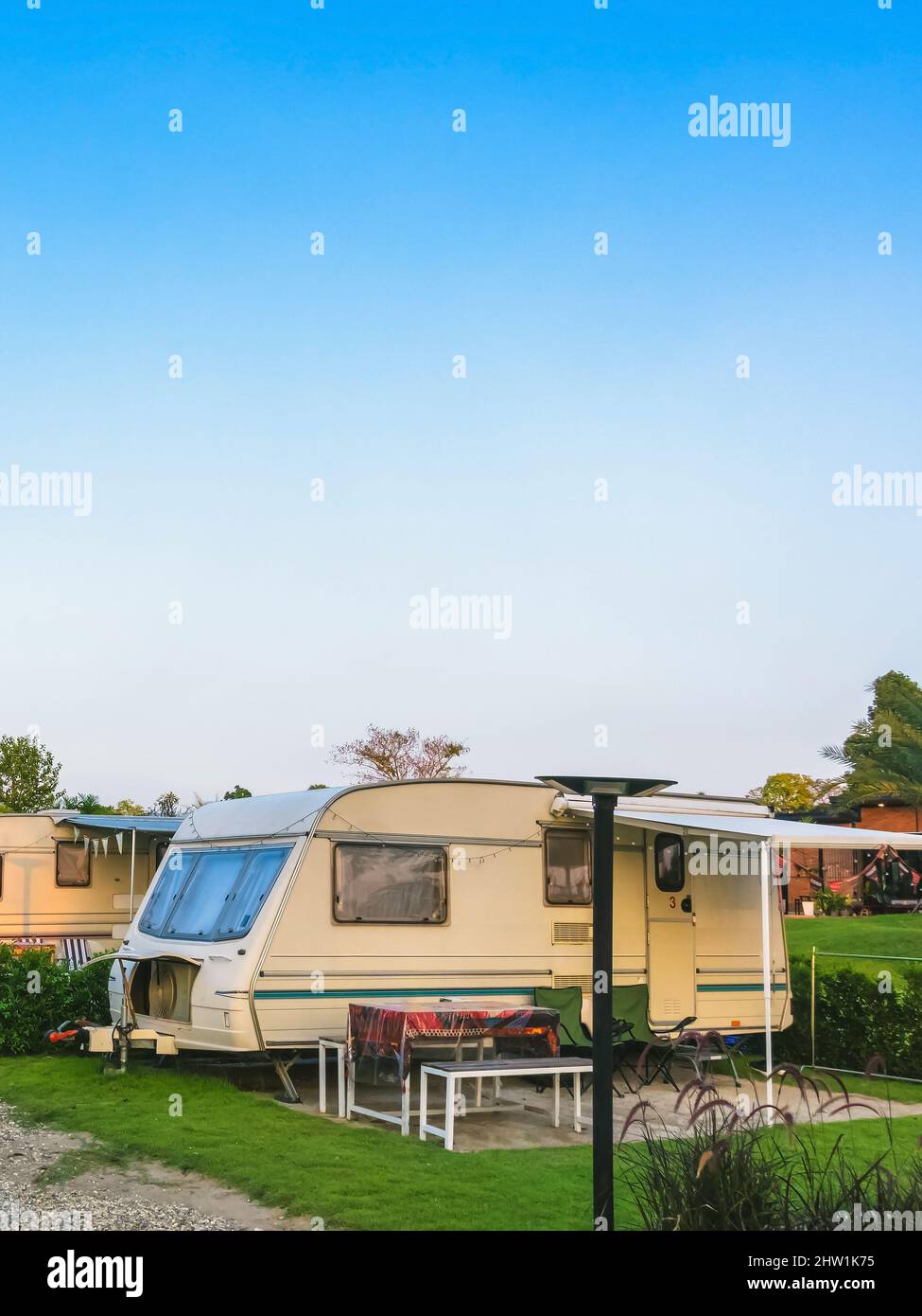Cozy retro travel trailer Caravan on green grass before sunset near ...