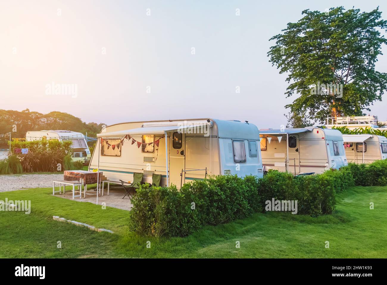 Cozy retro travel trailer Caravan on green grass before sunset near ...