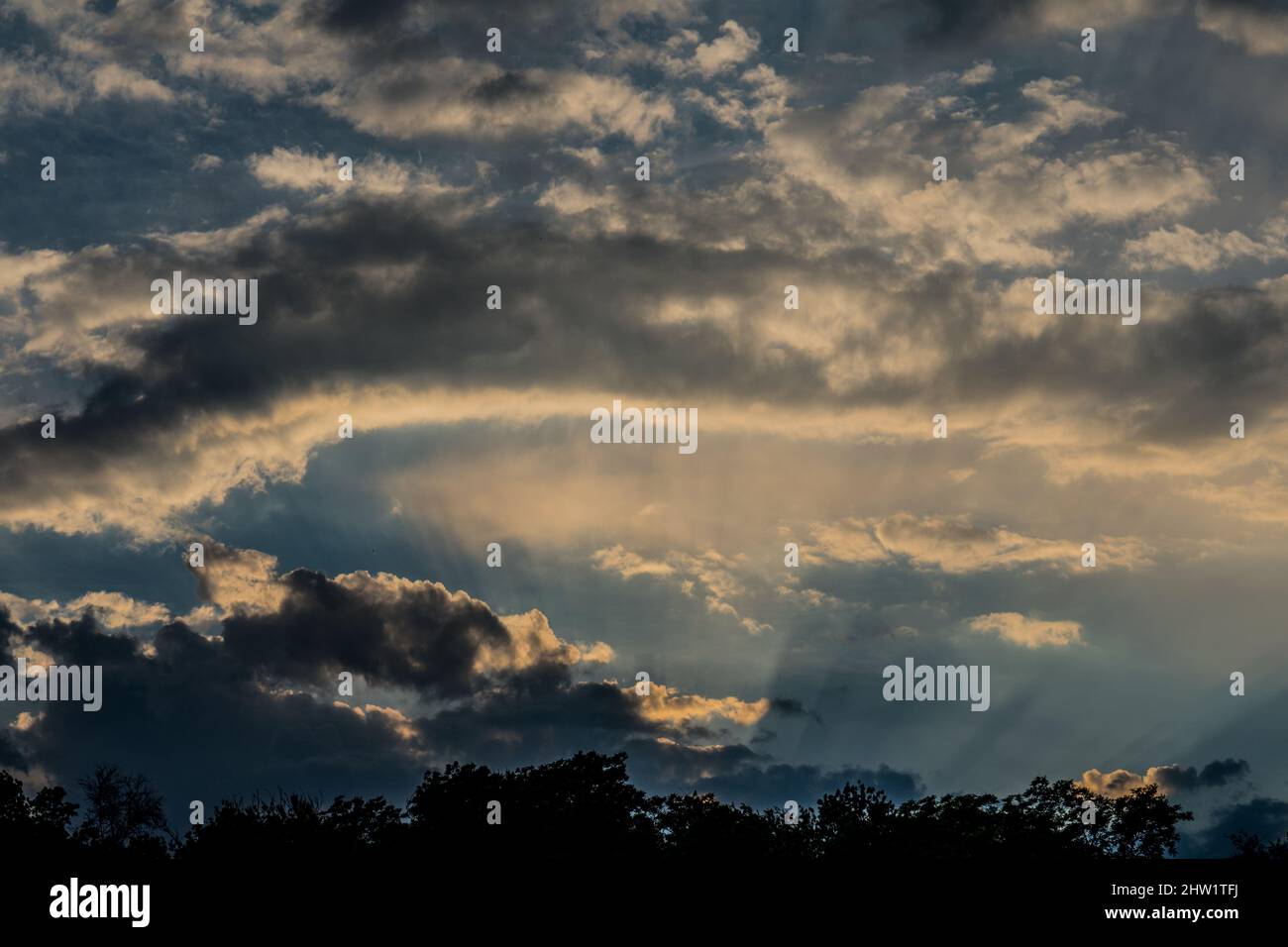 the sky is covered with dark gloomy clouds and the sun's rays seep ...