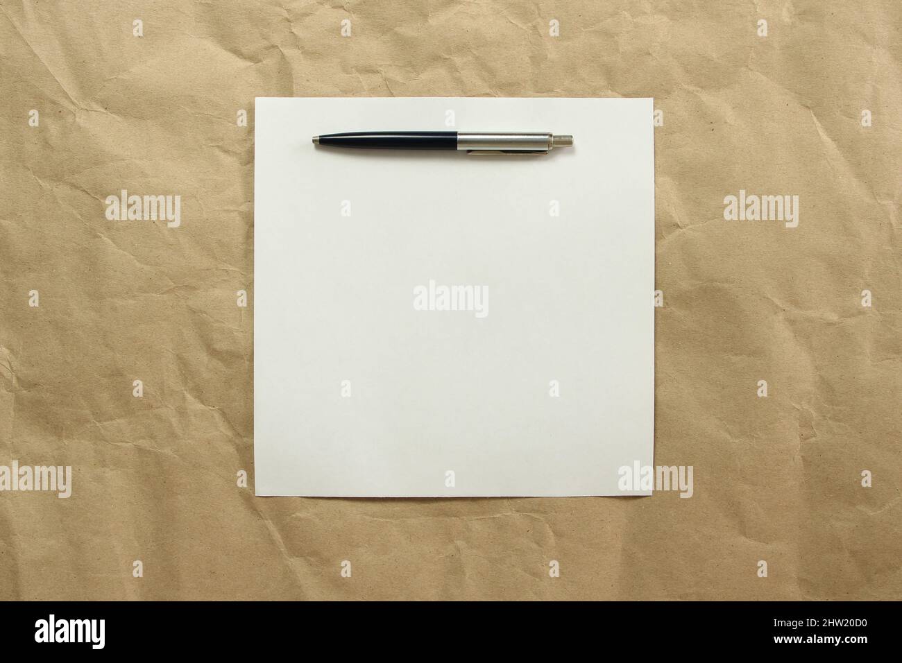 Square white empty sheet of paper with pen on a beige craft paper ...