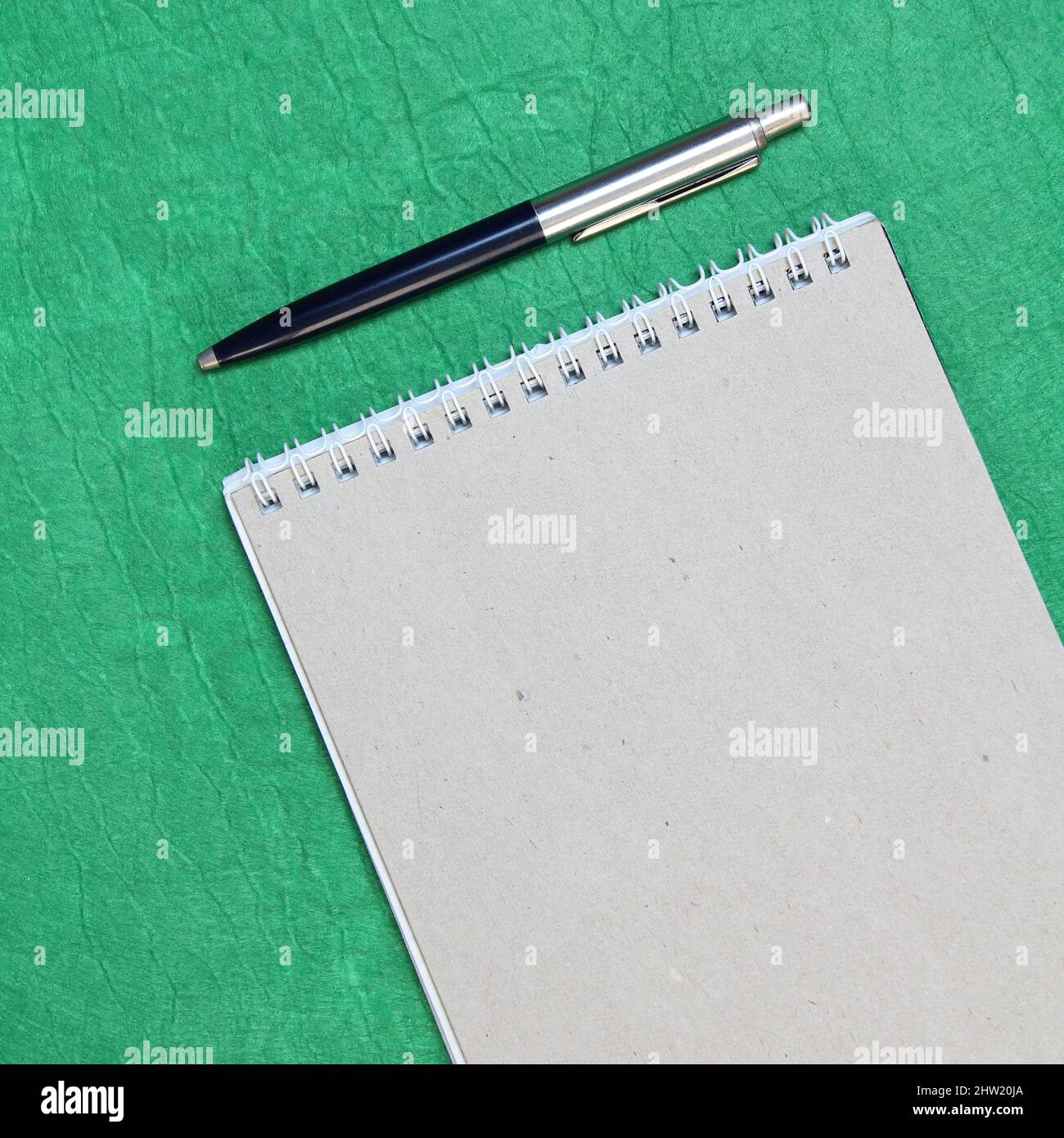 White and gray notepad sheet with spiral with pen against the ...
