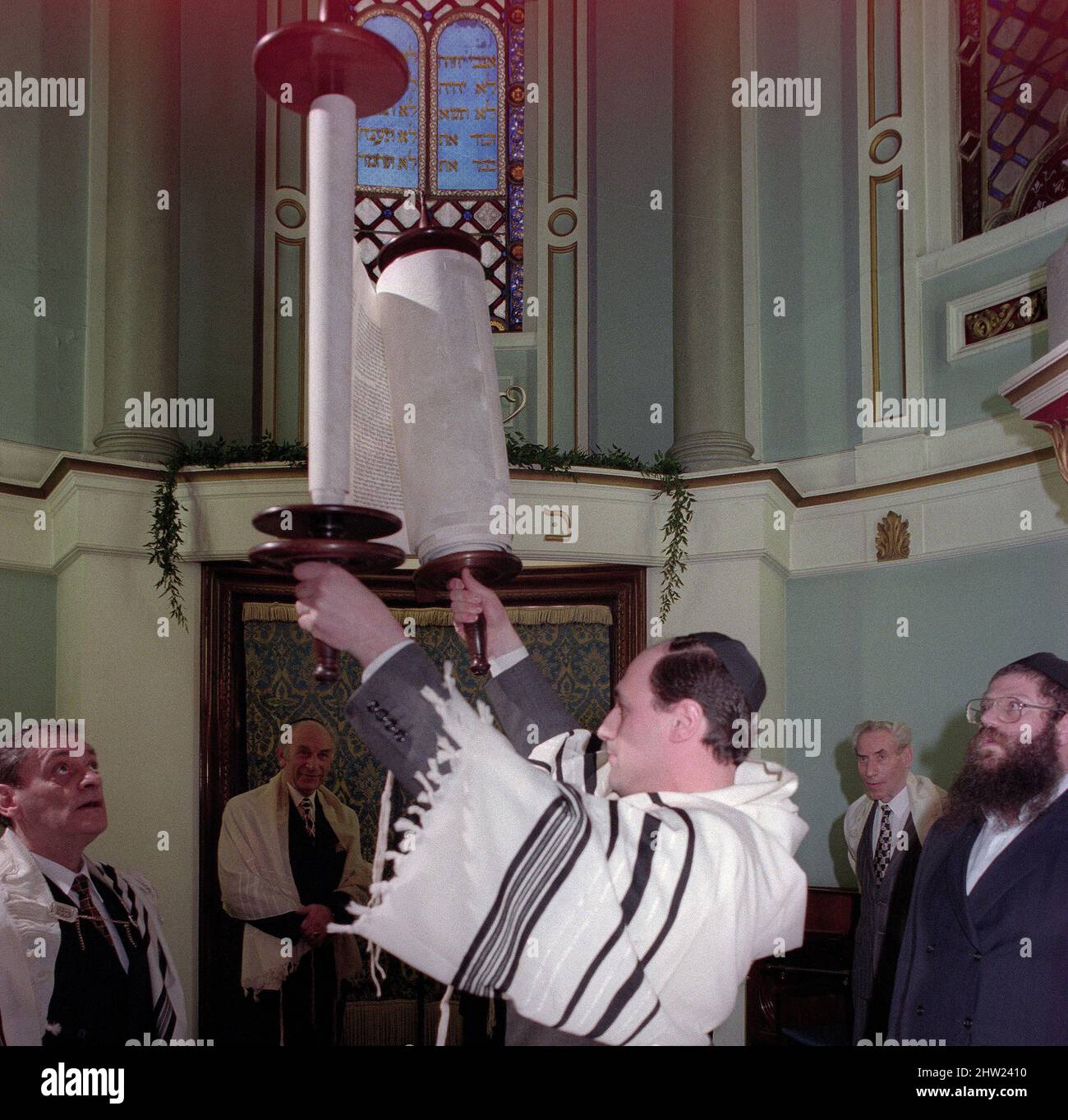 The new Sefer Torah is raised high for the Hagbah ceremony. The Chief ...