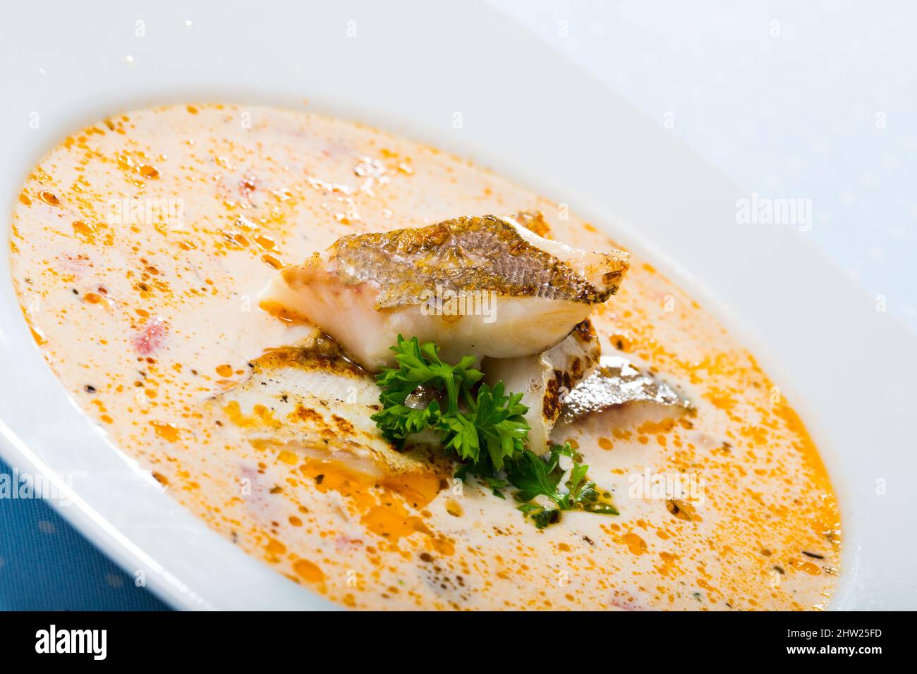 Tasty creamy soup with white fish cod and greens at white plate Stock ...