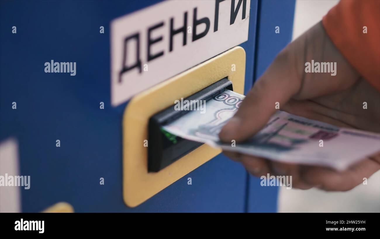 Person's hand sticks a paper money bill into the banknote bill acceptor ...