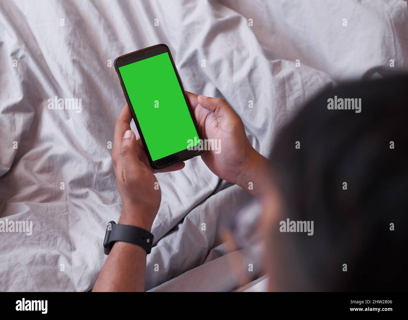 An over the shoulder shot of a mobile phone, man sitting in bed. Chroma ...
