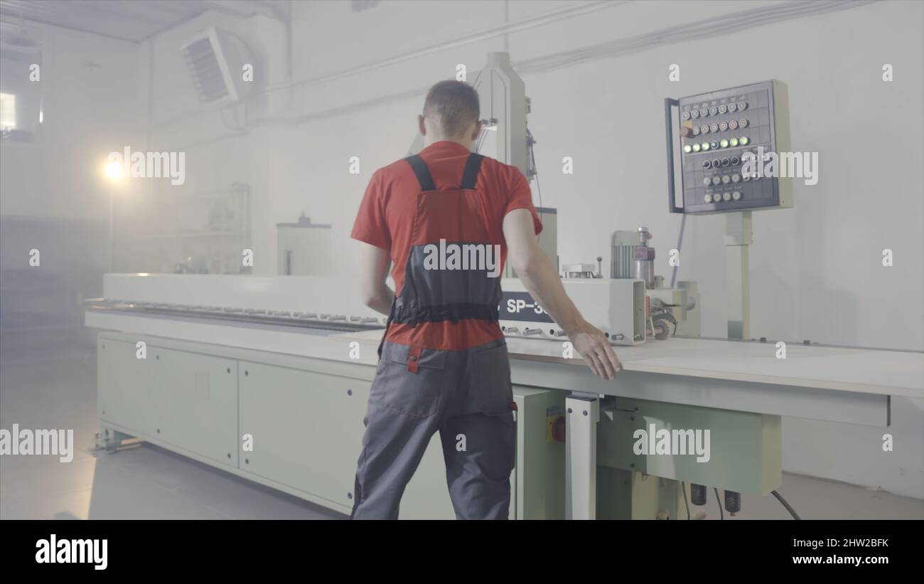 Worker working at sawing machine in production. Action. Worker controls ...