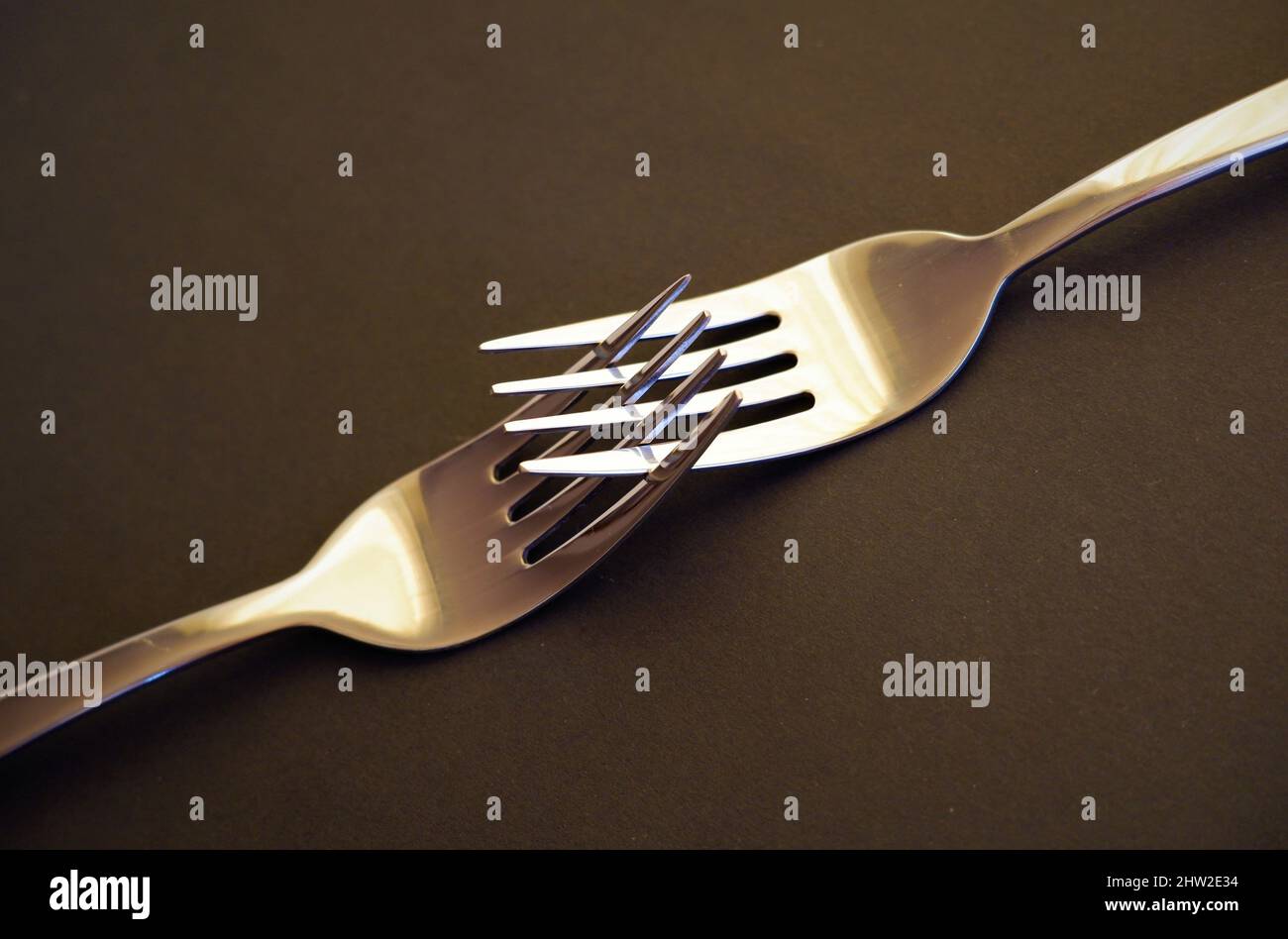 Two crossed shiny metal forks on the black surface Stock Photo - Alamy