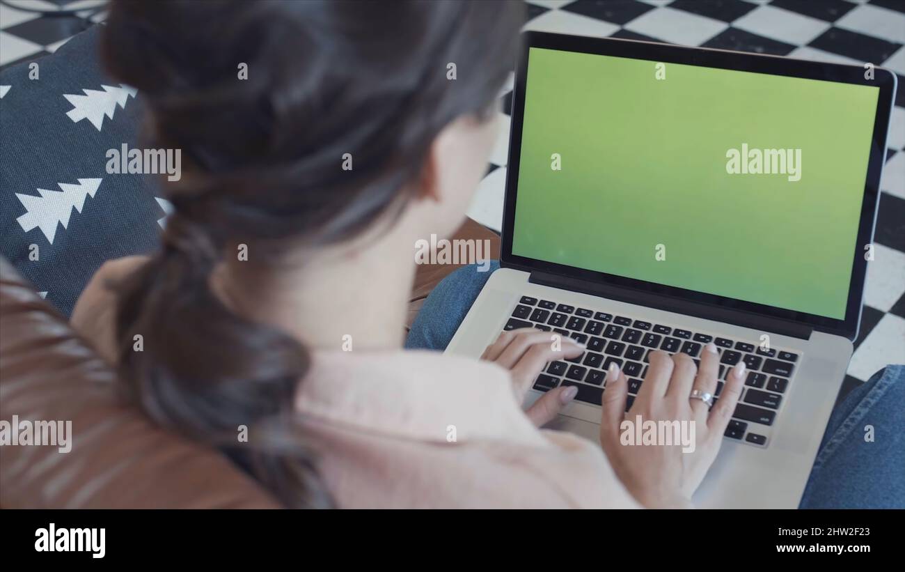 View of young woman in pink at home typing on the keyboard and looking ...