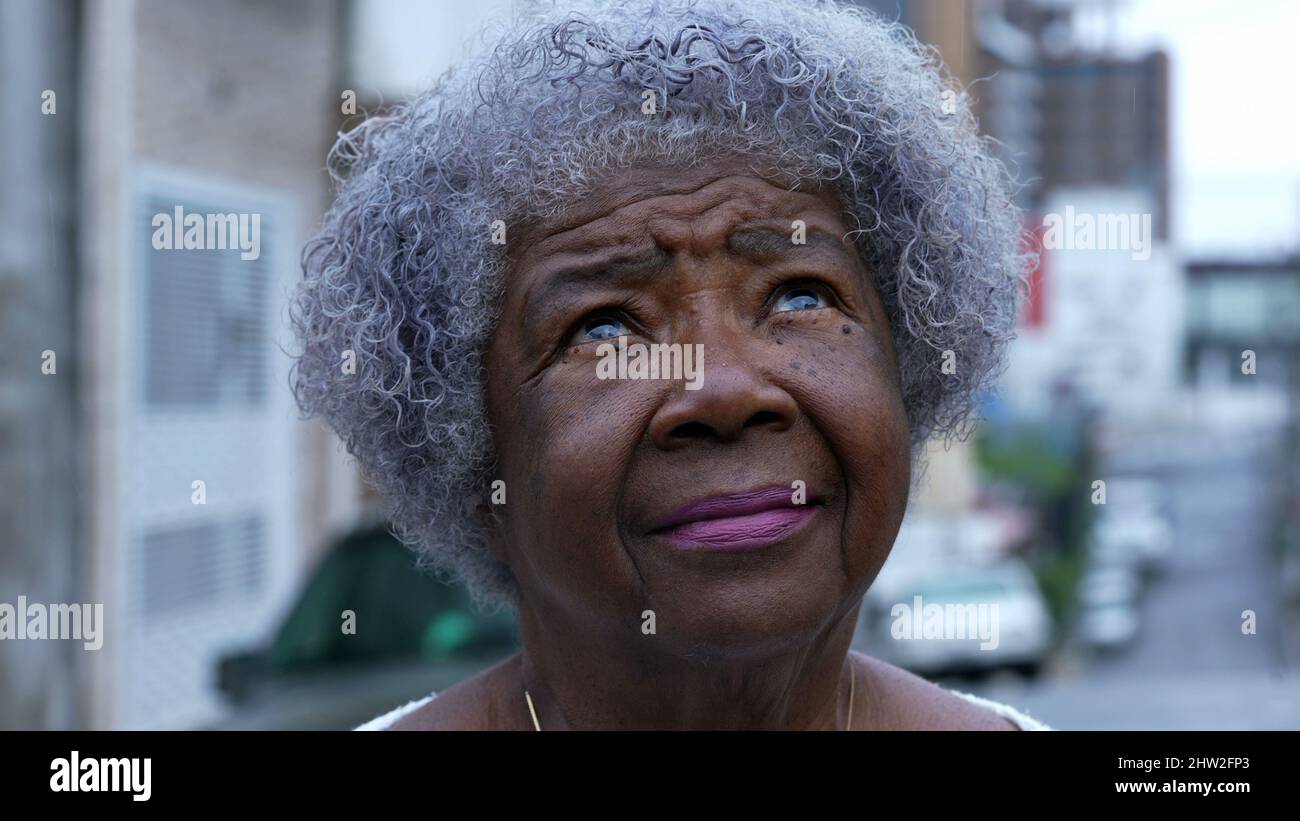 A contemplative senior black woman looking up at sky an African person ...