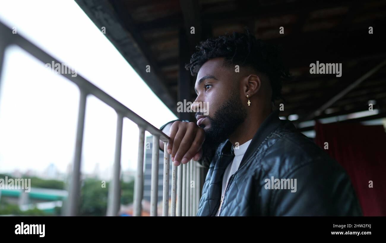 A pensive black man standing on balcony thinking about life Stock Photo ...