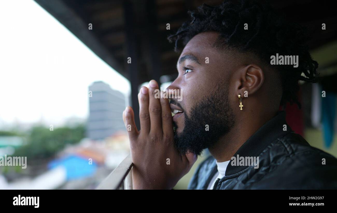 A young black man praying to God person opening eyes to sky smiling ...