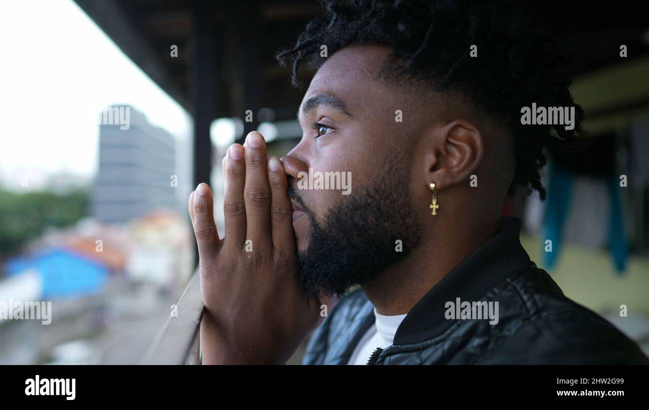A young black man praying to God person opening eyes to sky smiling ...