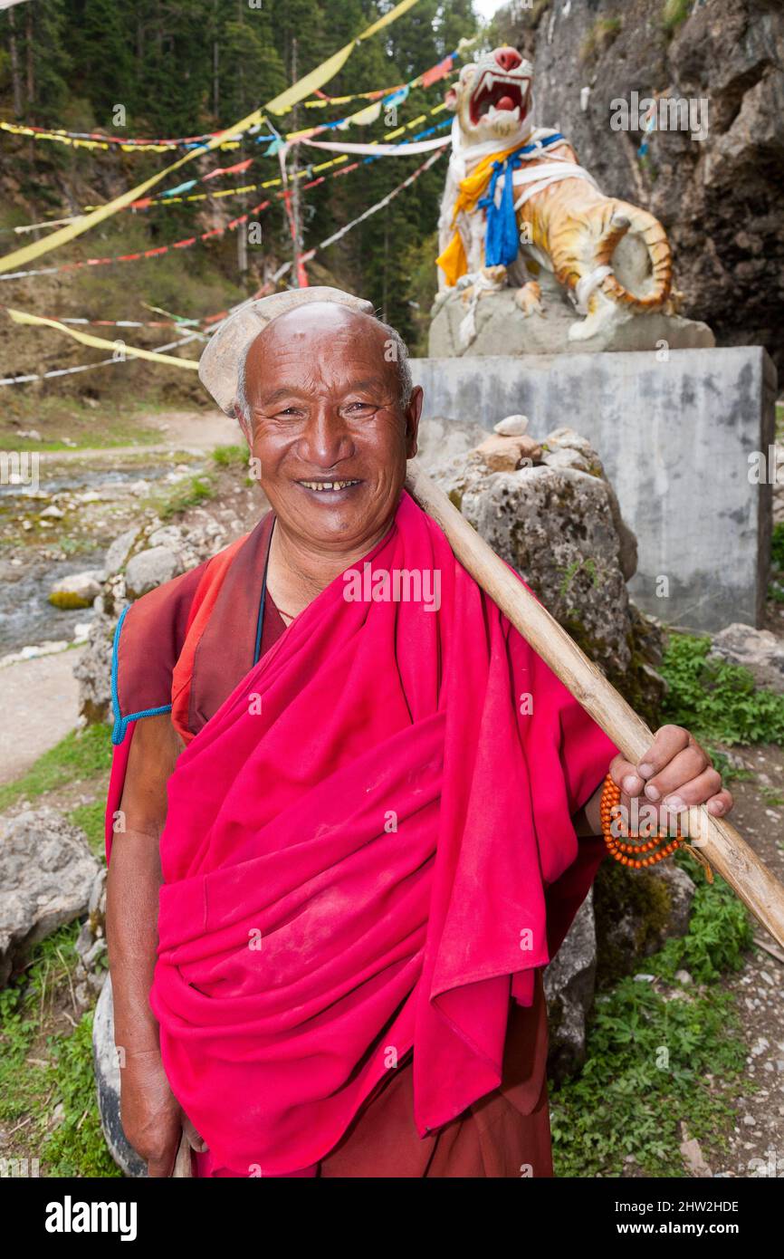 Middle aged Buddhist monk of Tibetan heritage, in crimson red robe ...