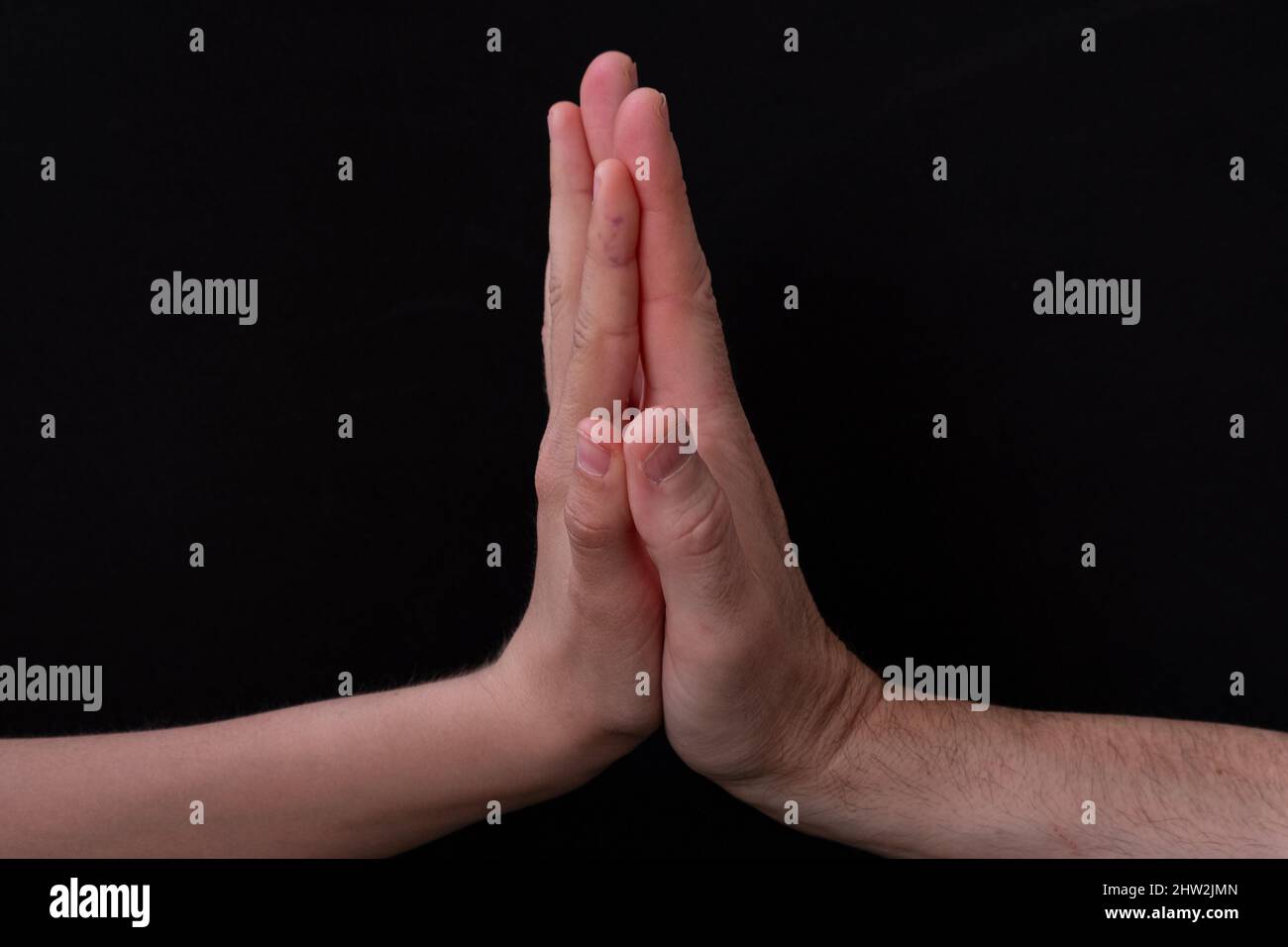 Hand of a man and a woman touching their palms on a black background ...