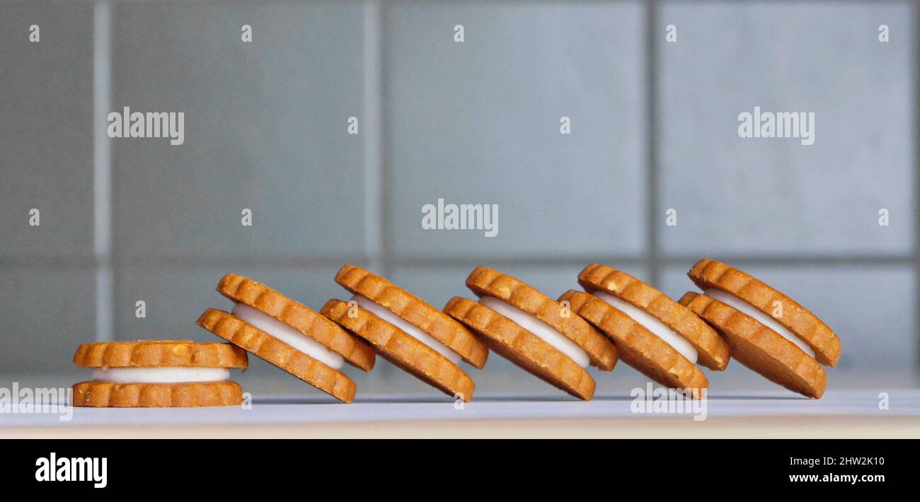 Five round cookies with white filling lie one on one in a row on a ...