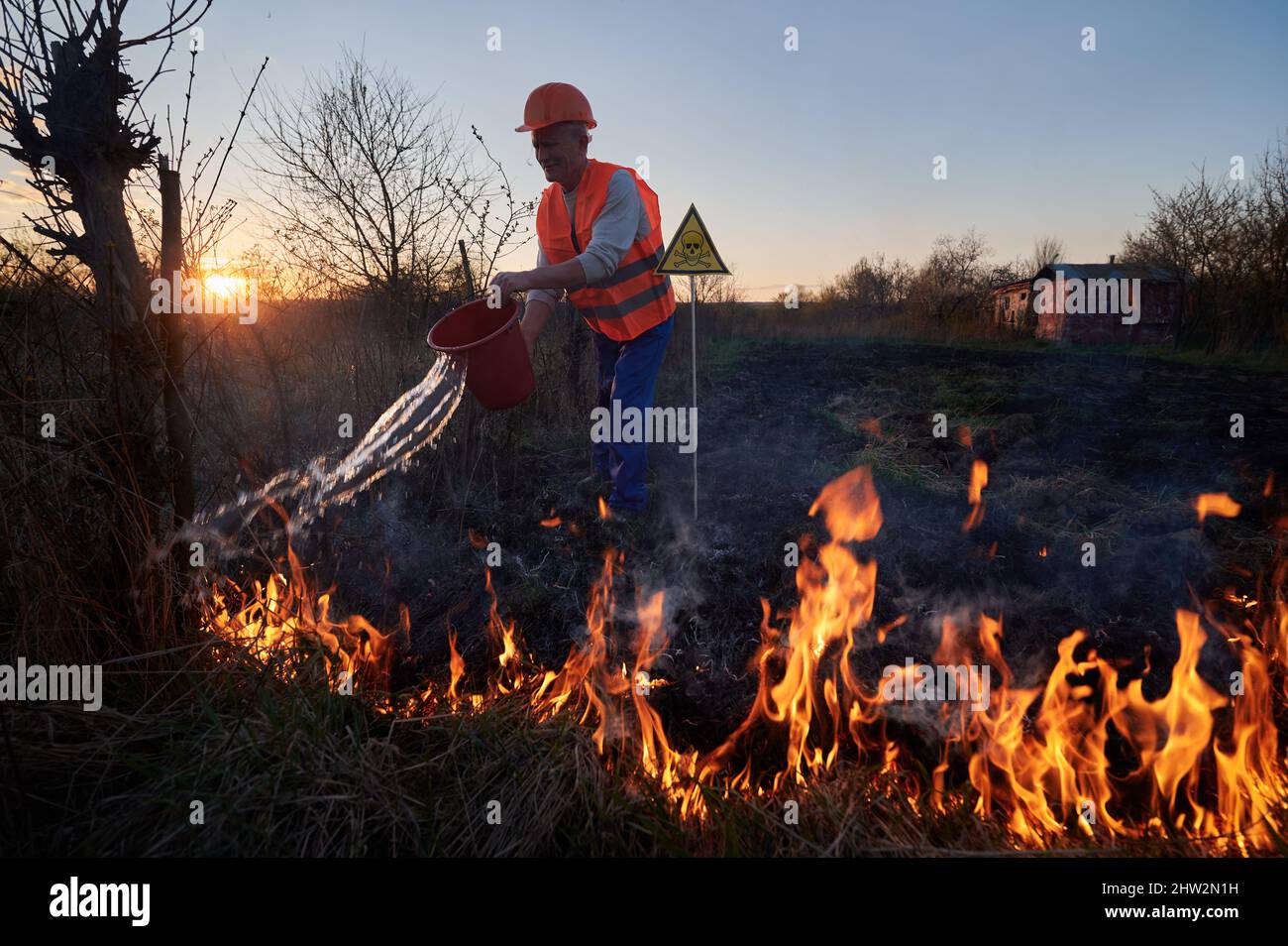 Fireman ecologist fighting wildfire in field with evening sky on ...