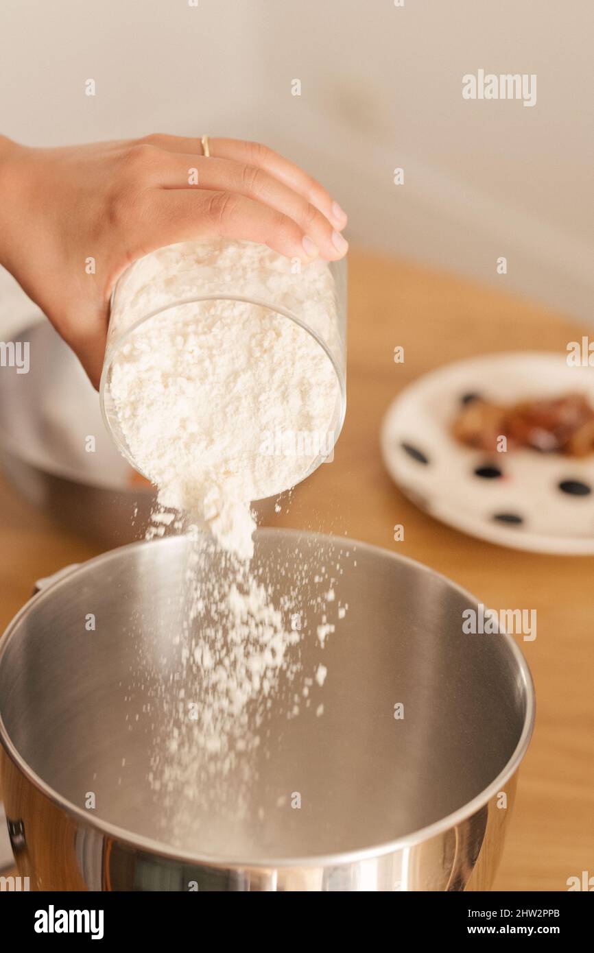Closeup of a hand adding Wheat Flour on water on a metal bowl in the ...