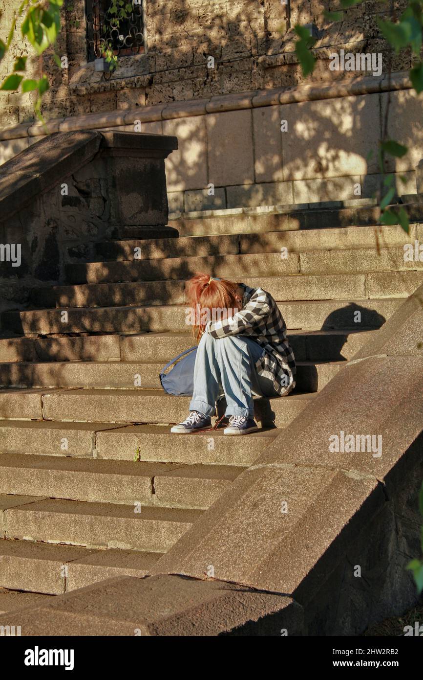 Vertical shot of a teenage girl sitting on the stairs portraying ...