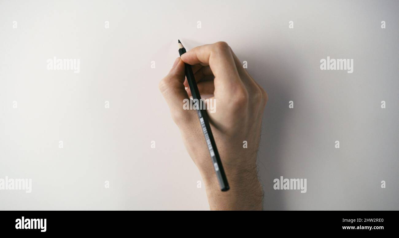 Hand of a man holding a pencil over white paper preparing to draw ...