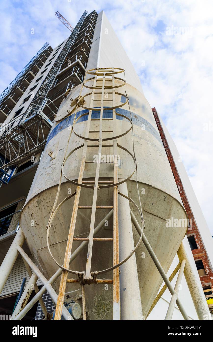 Storing sand in a silo next to the scaffolding of a building ...