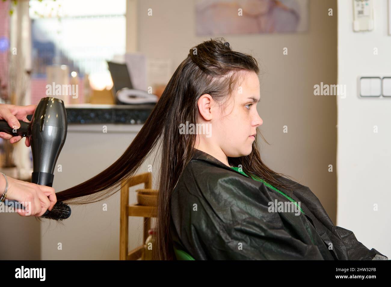 Hairdresser dries and styles the hair with a hair dryer in the beauty ...