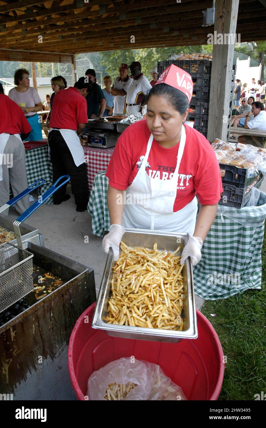 Woman making battered French Fries and Onion Rings for party in deep ...