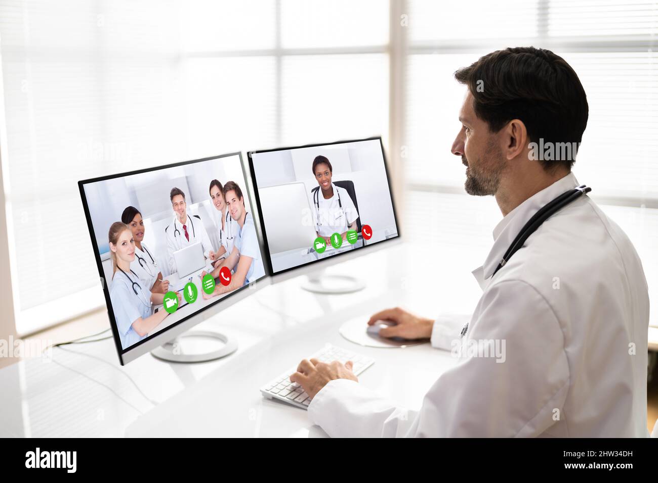 Young Male Doctor Video Conferencing With Medical Team On Computer Desk ...