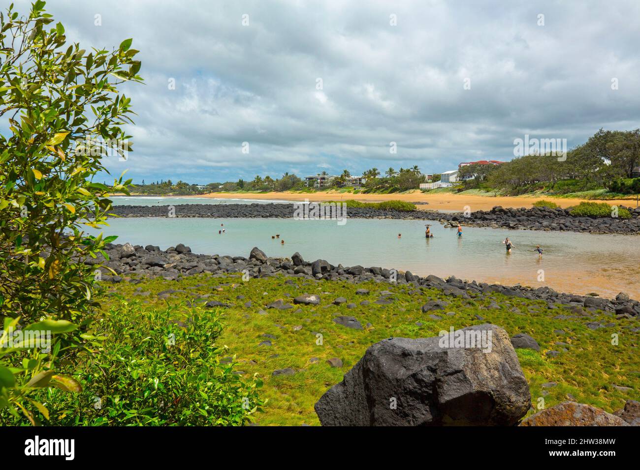 Sandy beach and The Basin rock pool at Bargara with people cooling off ...