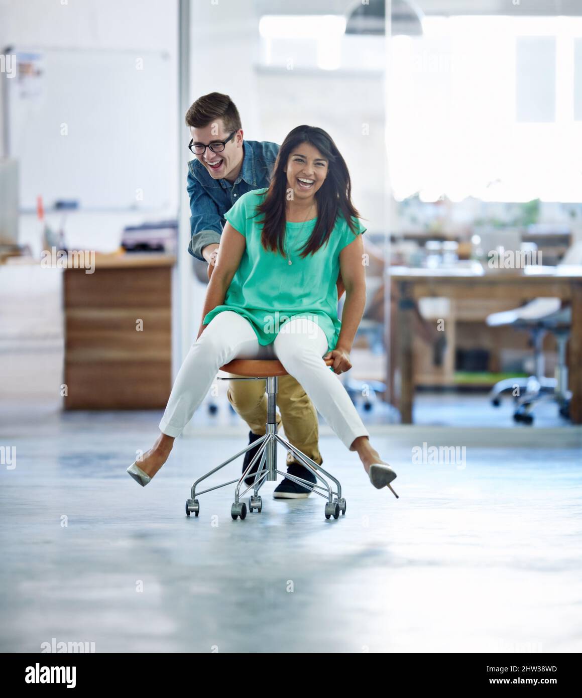 Having a blast in the office. Shot of a male coworker pushing his ...