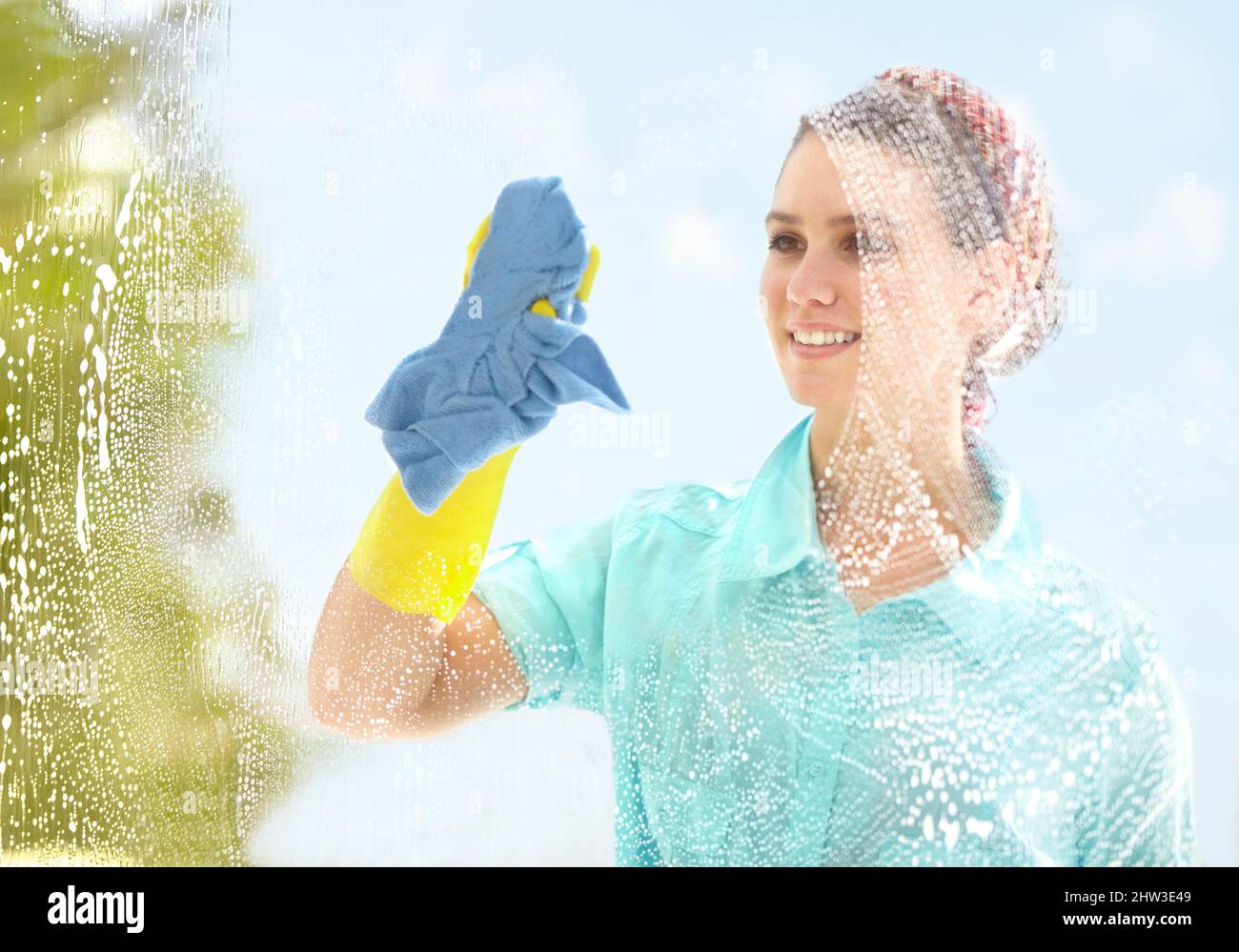 Making sure its clean and streak-free. Young woman washing her windows ...