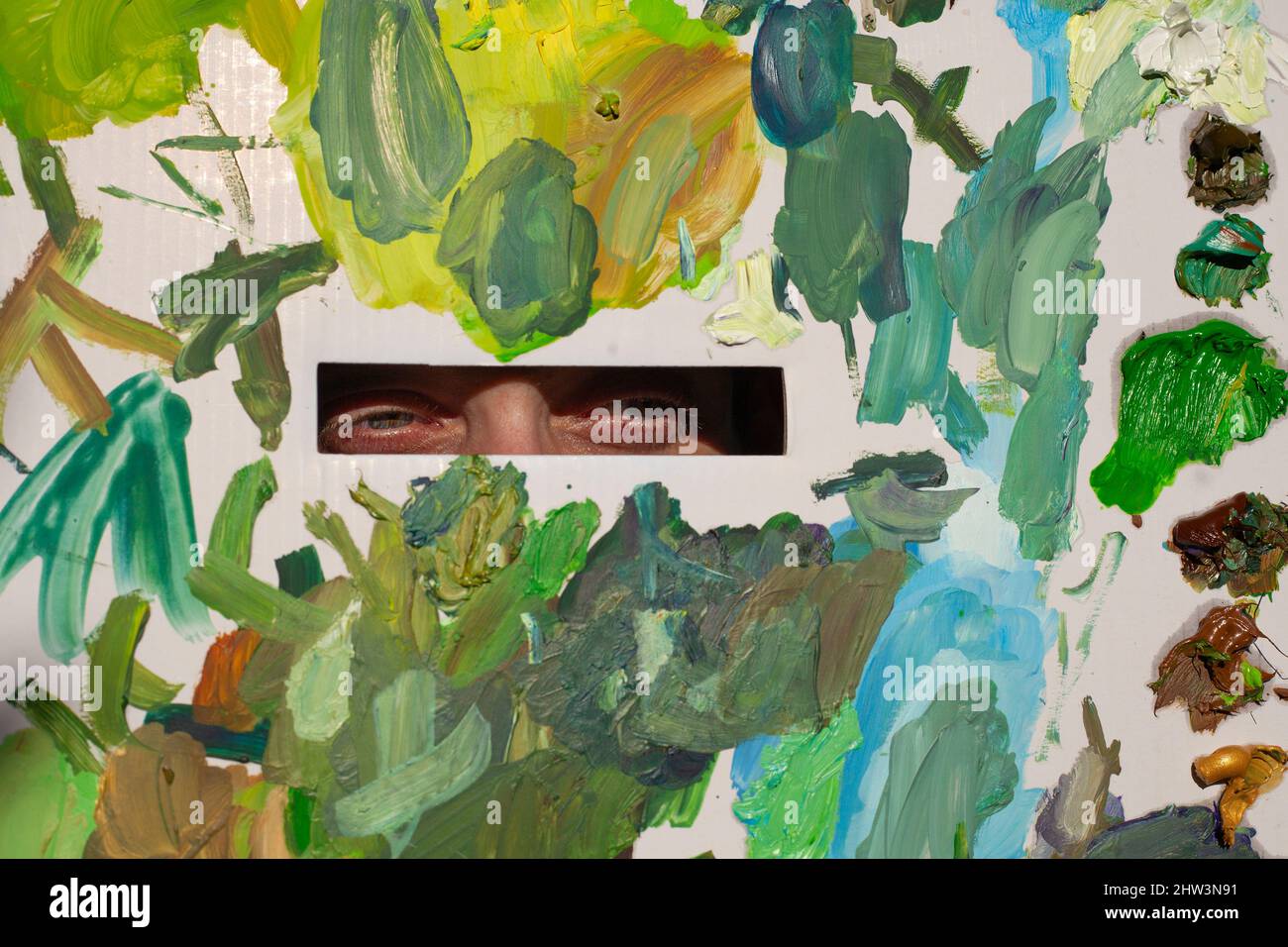 The guy is looking at you through a slot in the palette. Artist looks ...