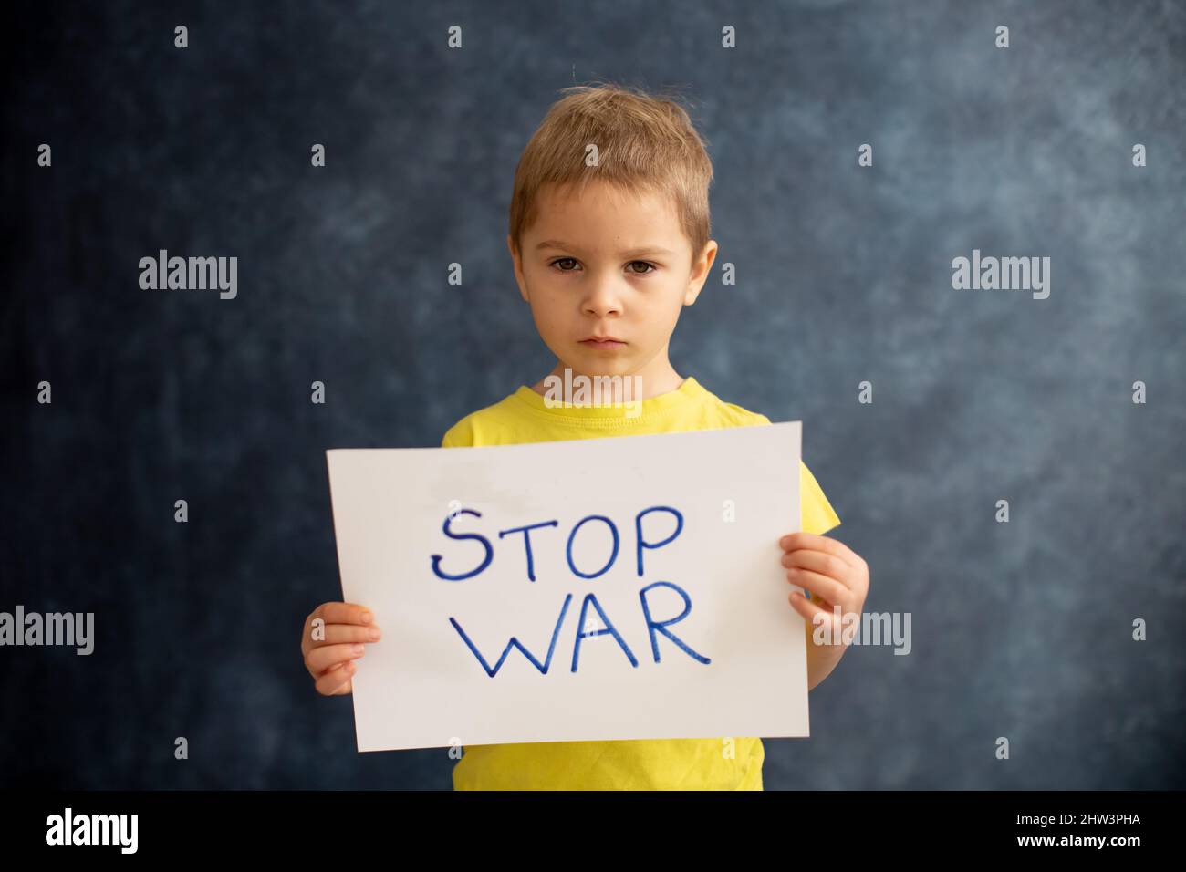 Young blond child, holding sign in support to peace, no war wanted, kid ...