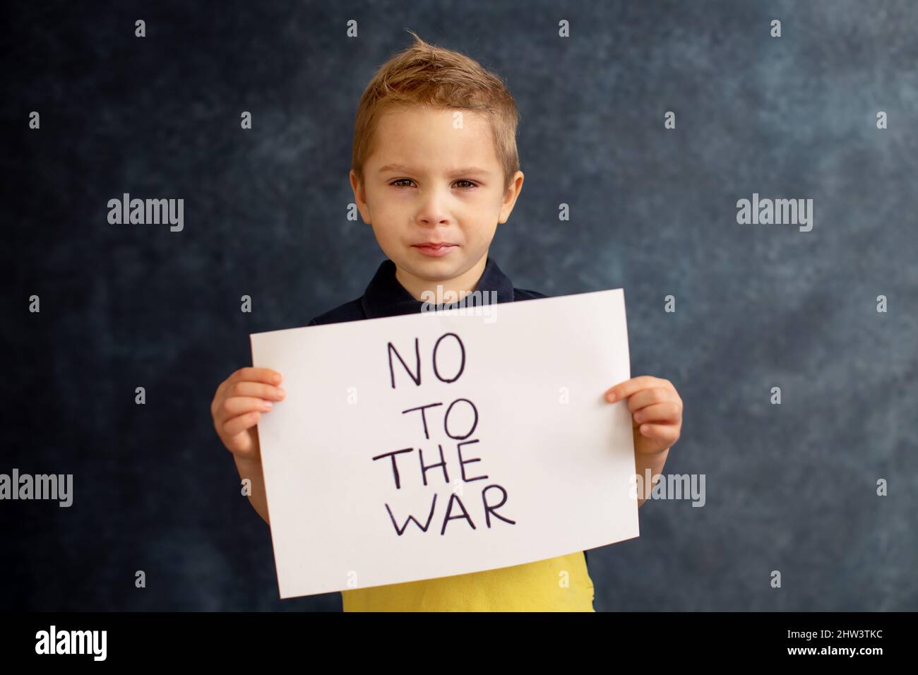 Young blond child, holding sign in support to peace, no war wanted, kid ...