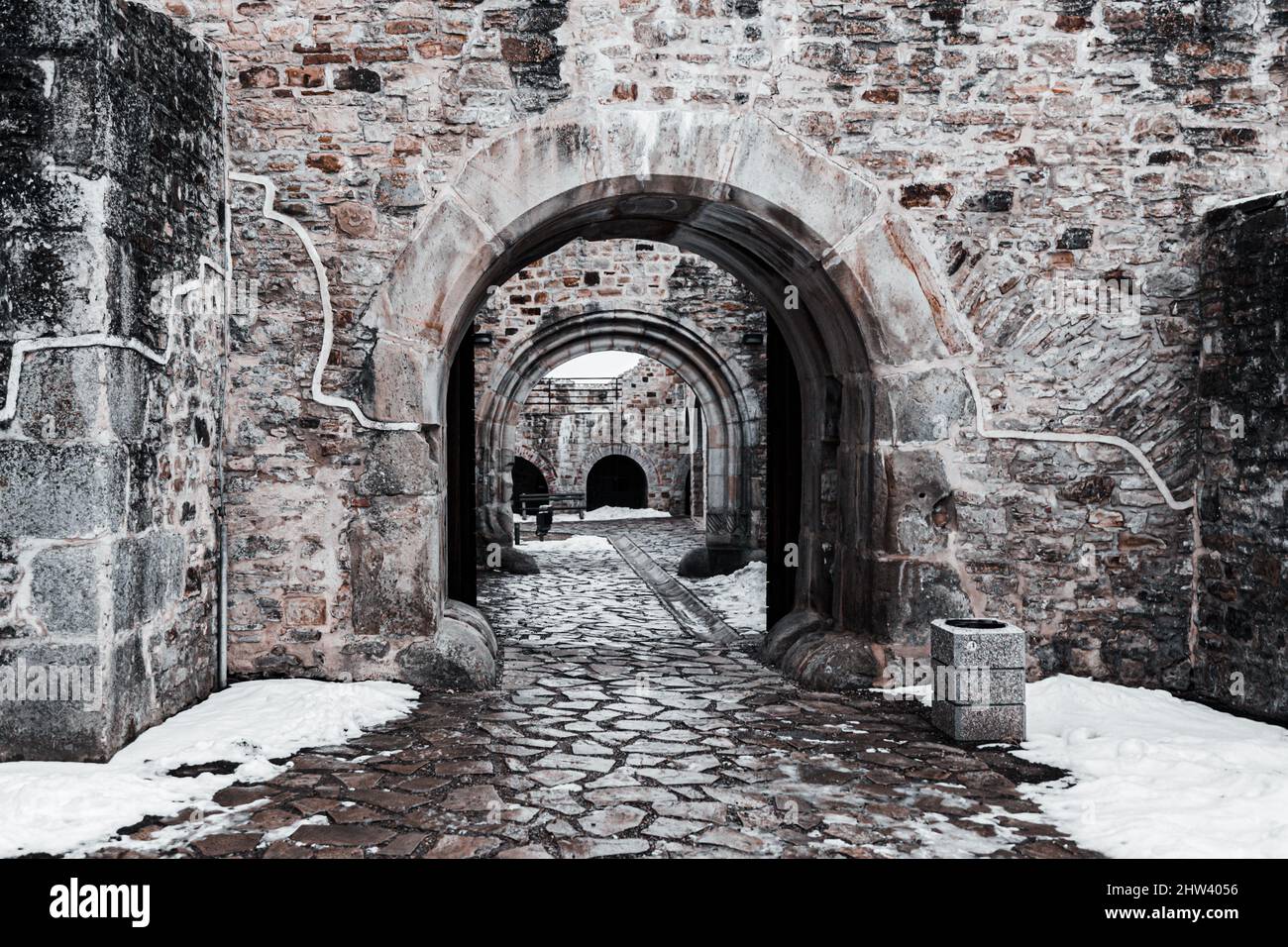 Beautiful shot of an old stone arch gate of a castle with a tiled stone ...