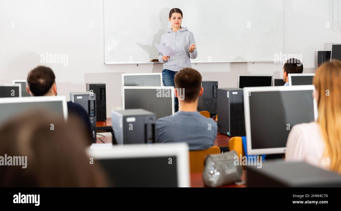 Young female trainer giving presentation to adult audience in computer ...