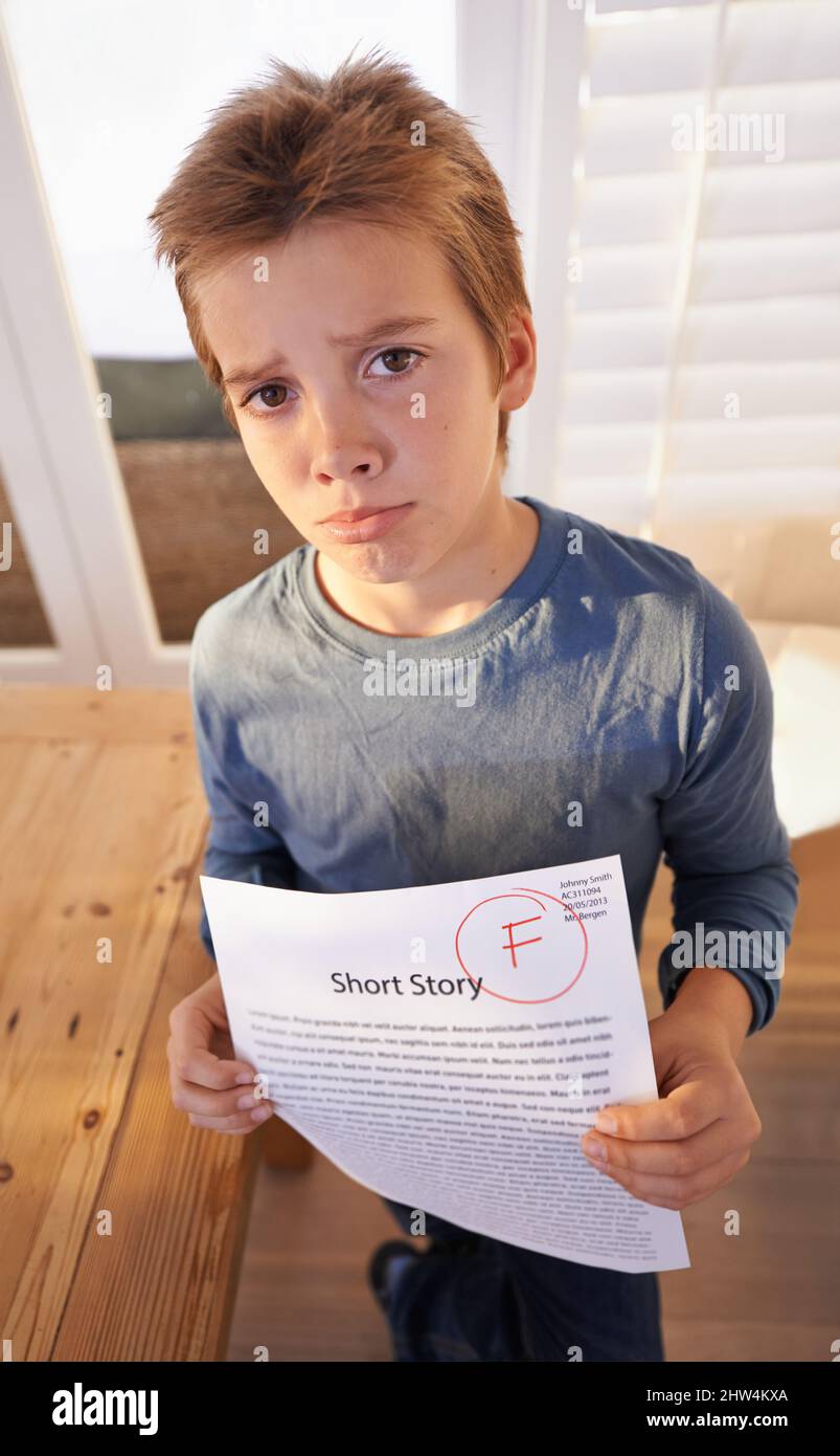 F is for failure. Shot of a sulking young boy holding up a paper that ...