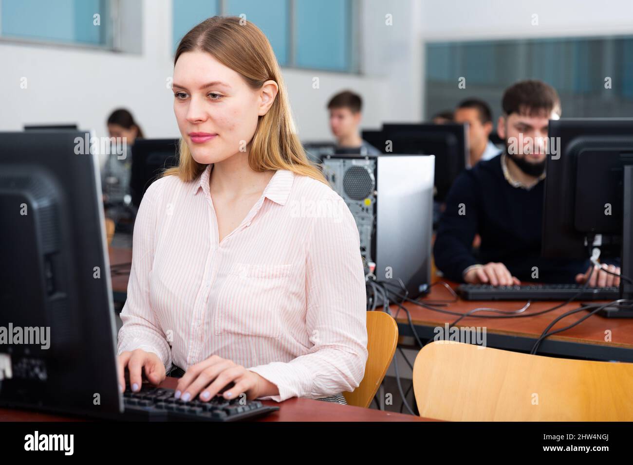 Portrait of female and male students working on computers in classroom ...