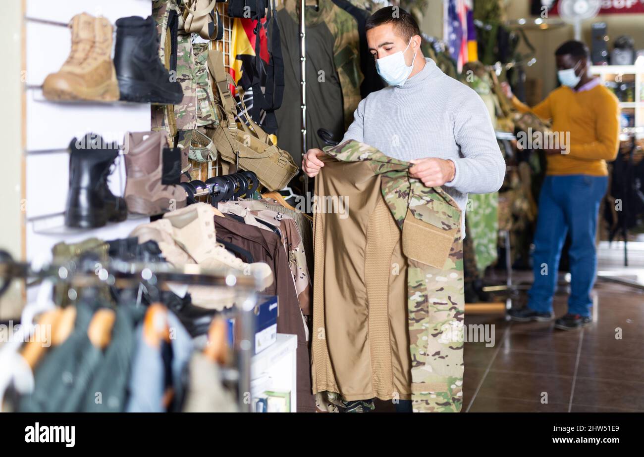 Man in protective mask chooses camouflage uniform at army store Stock ...
