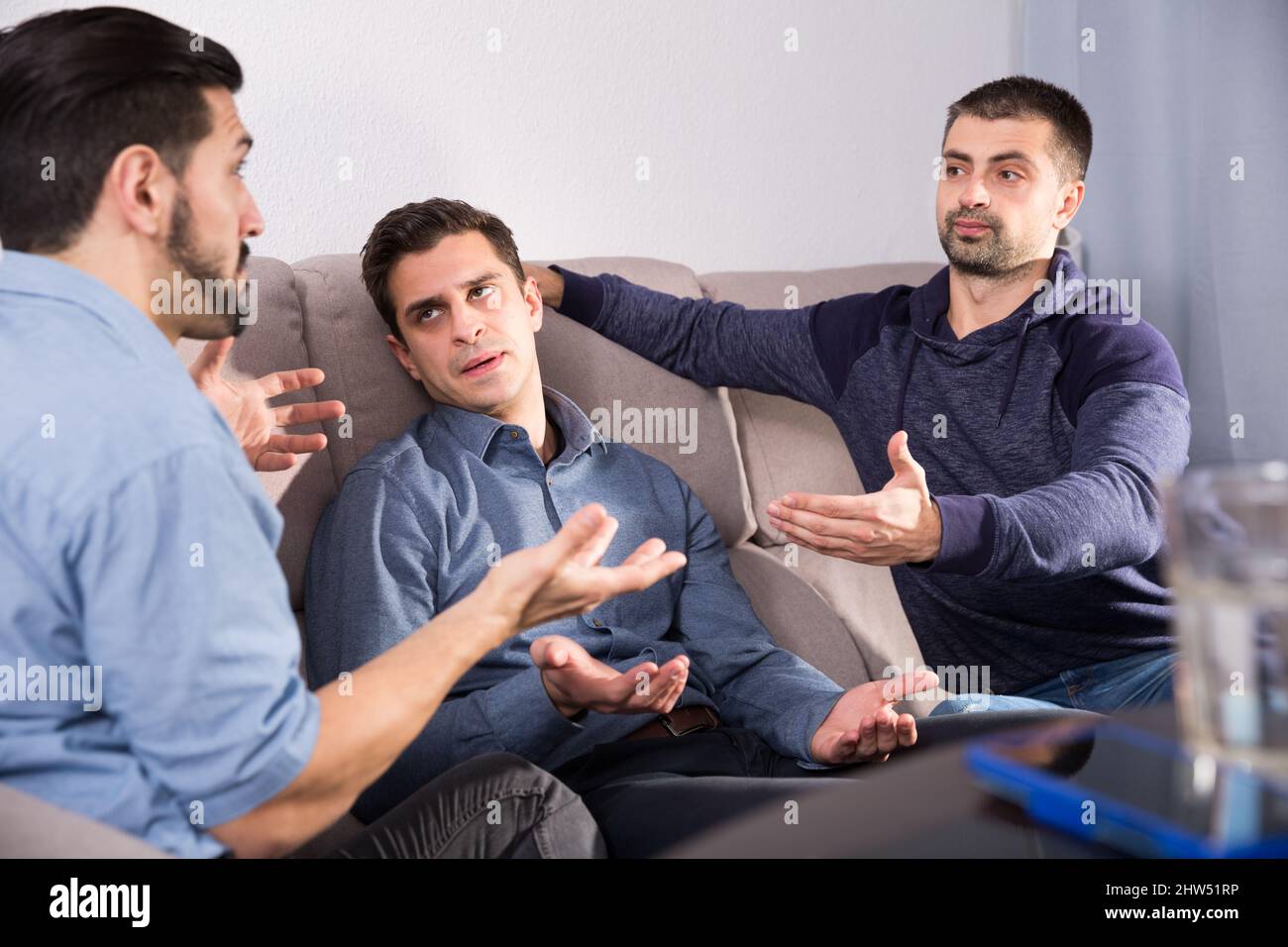 Upset friends talking on couch Stock Photo - Alamy